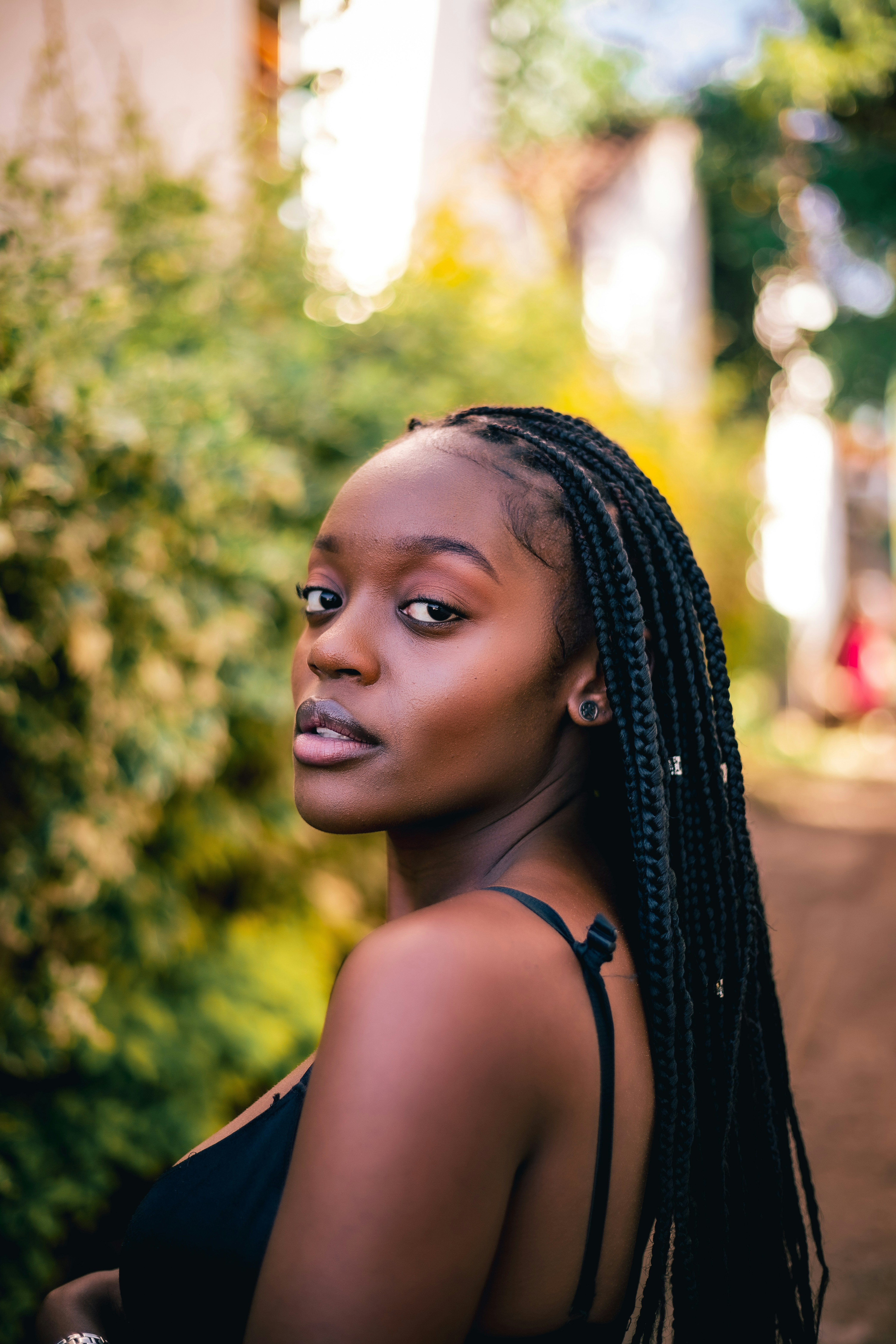 A woman with long braids standing in front of a bush photo – Free Adult ...