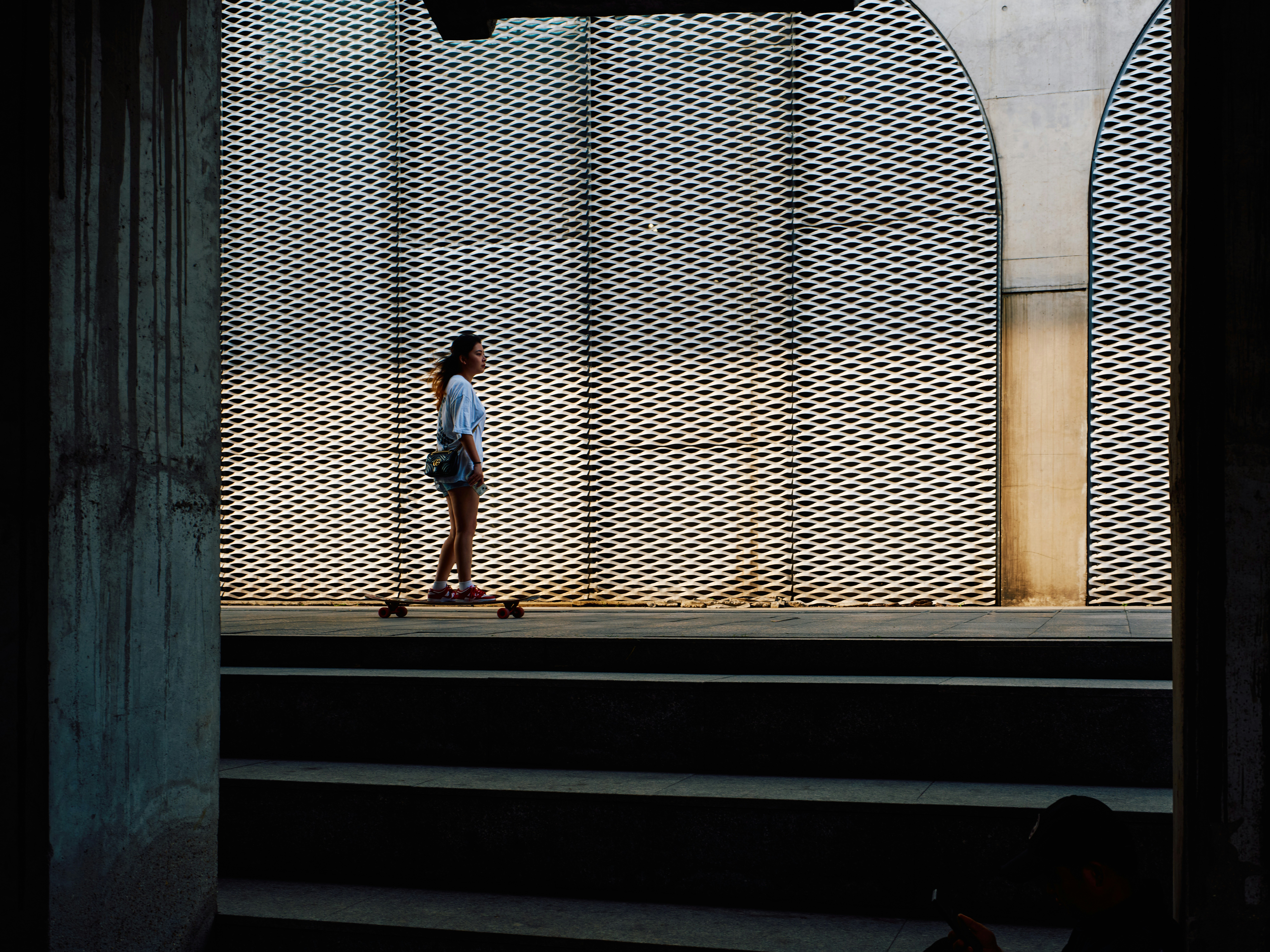 Longboarder in Quiet Focus Beneath a Repeating Wall Pattern
