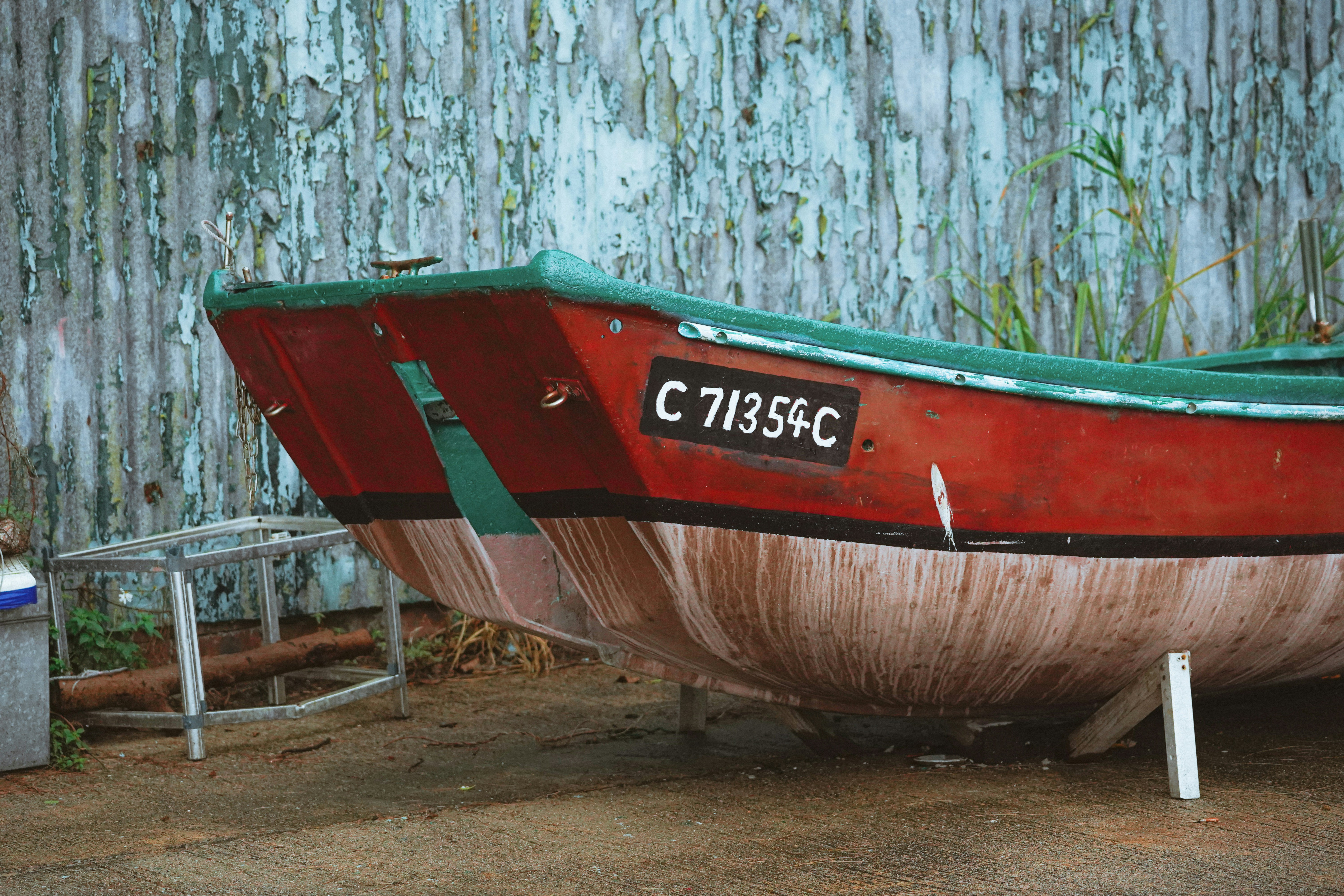Scarlet Hull Grounded: A Boat Framed by Weathered Green Walls