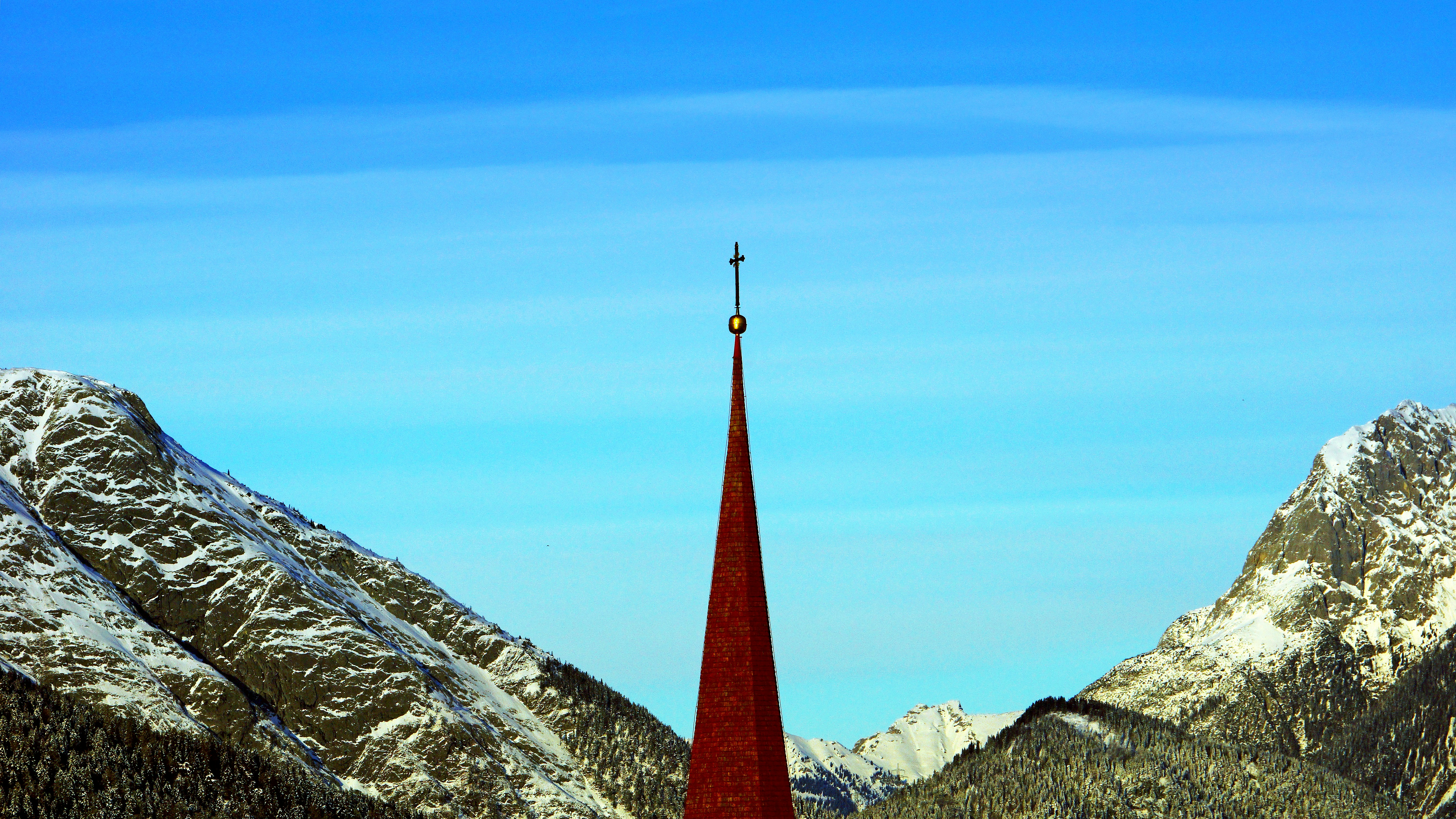 Alpine Cross: A Snow-kissed Peak Framed by a Towering Spire