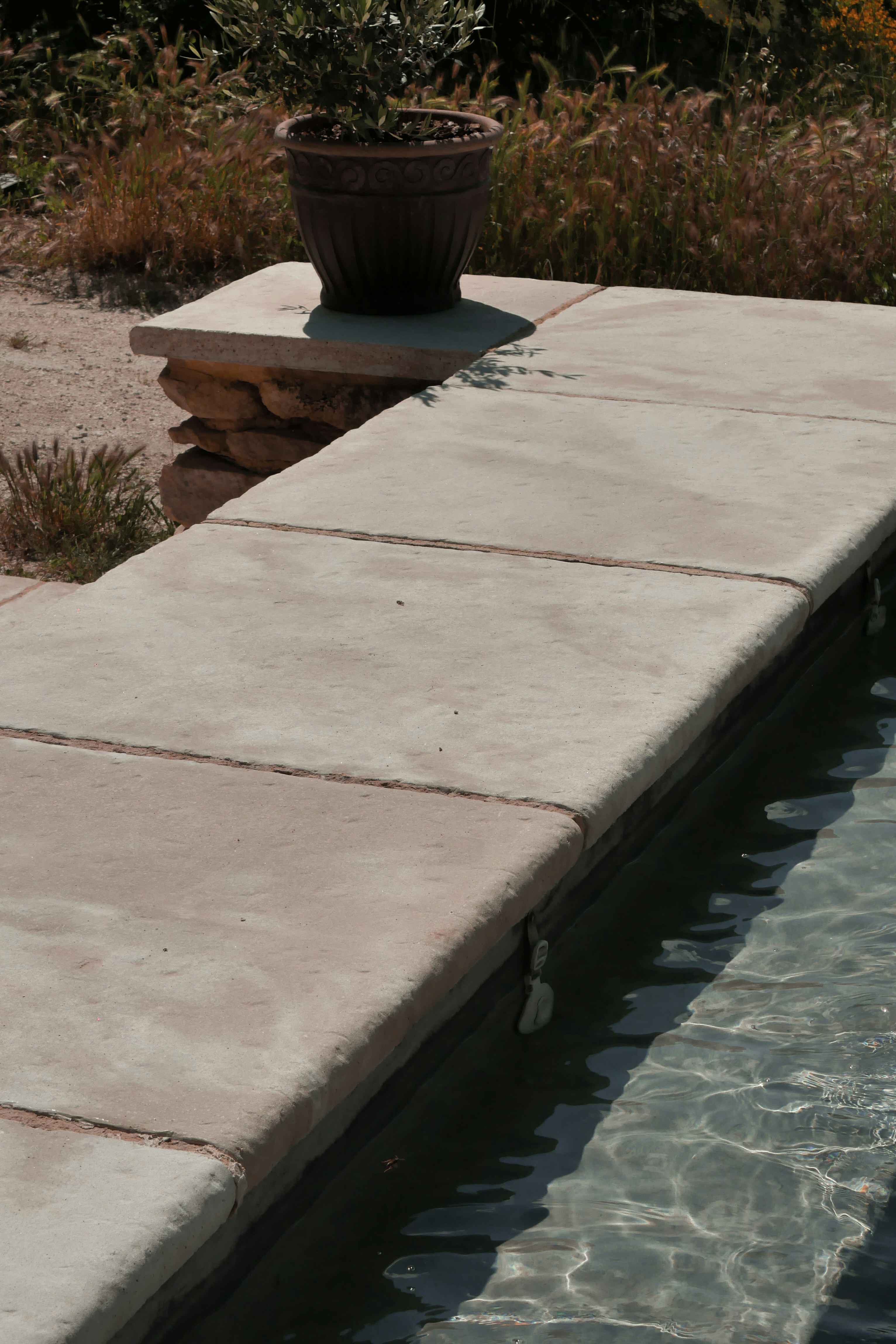 Terracotta Pot on a Stone Pedestal Guarding the Poolside Path