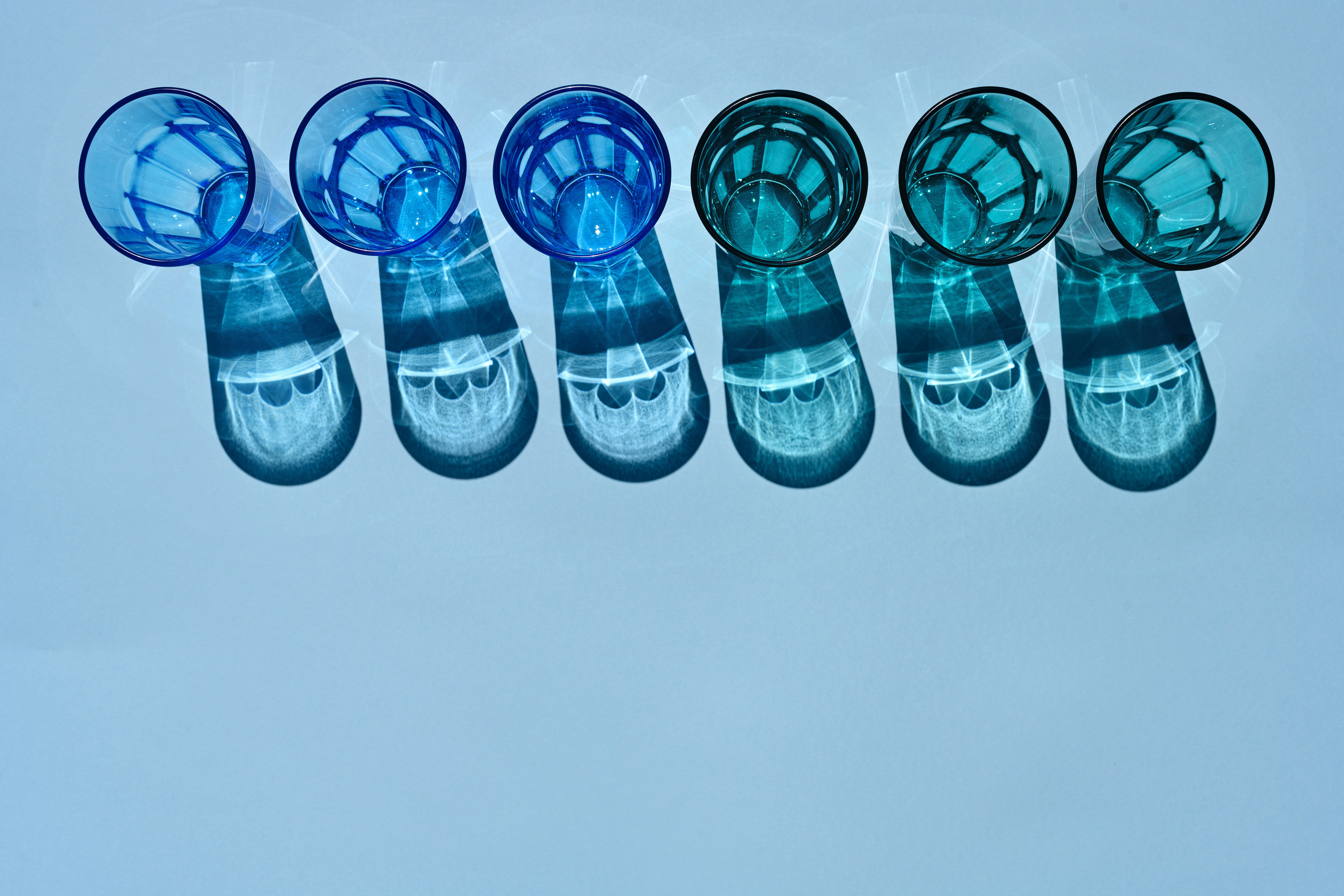 Cerulean Row: Translucent Cups Casting Quiet Shadows on a Sky-Blue Stage
