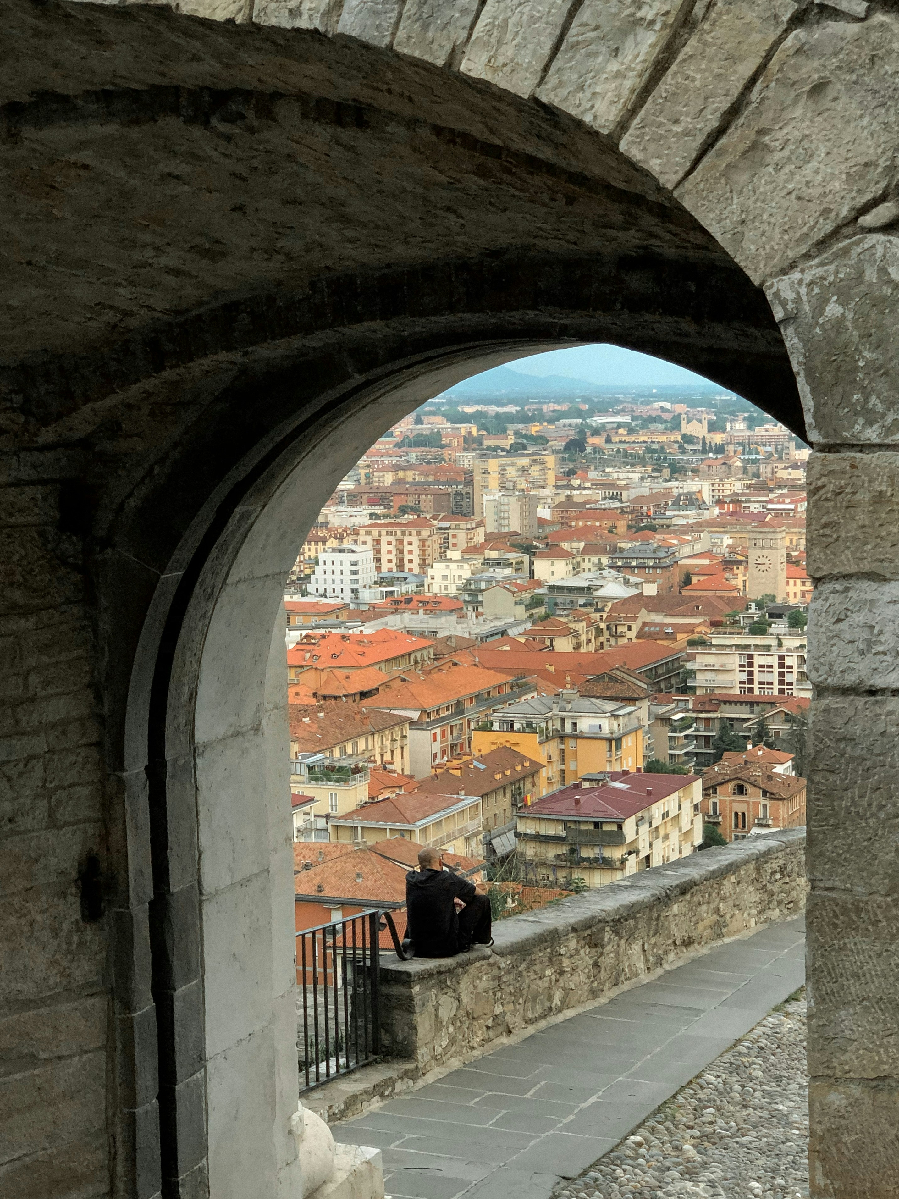 Stone Arch Framing a Terracotta-Roofted City
