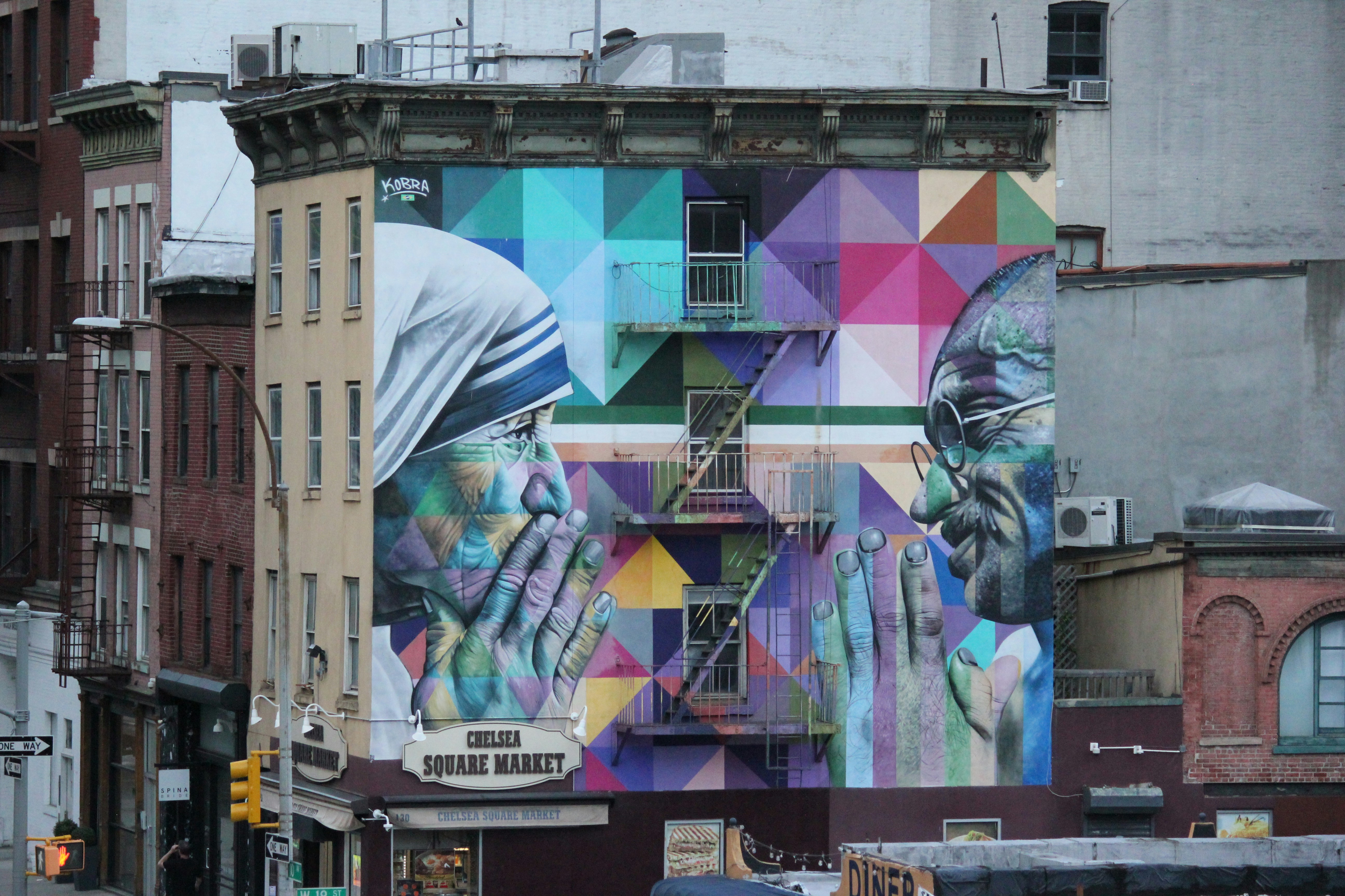 Colorful mural of two iconic figures in profile on a city building facade.