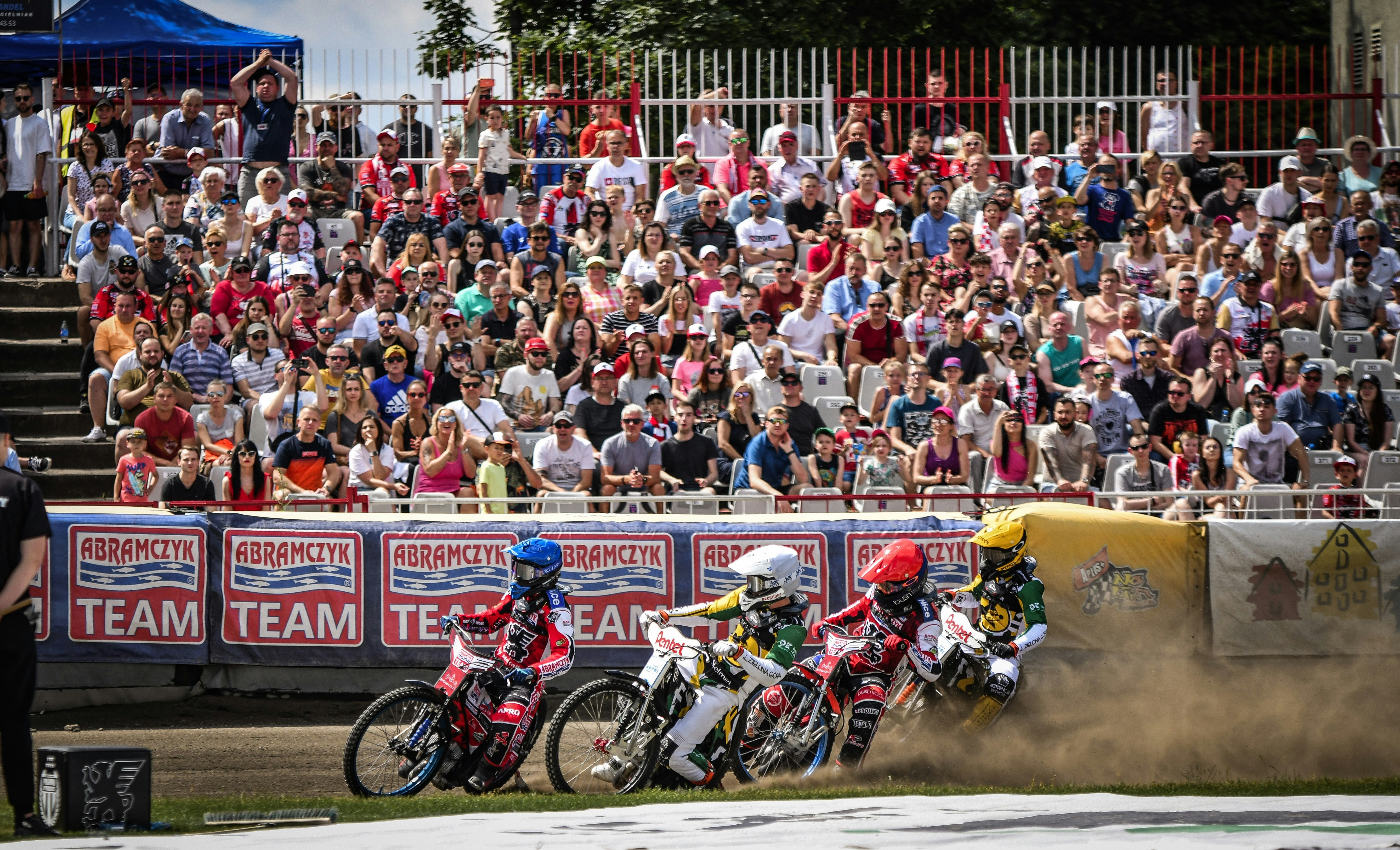 A group of motorcyclists racing around a track in front of a crowd ...