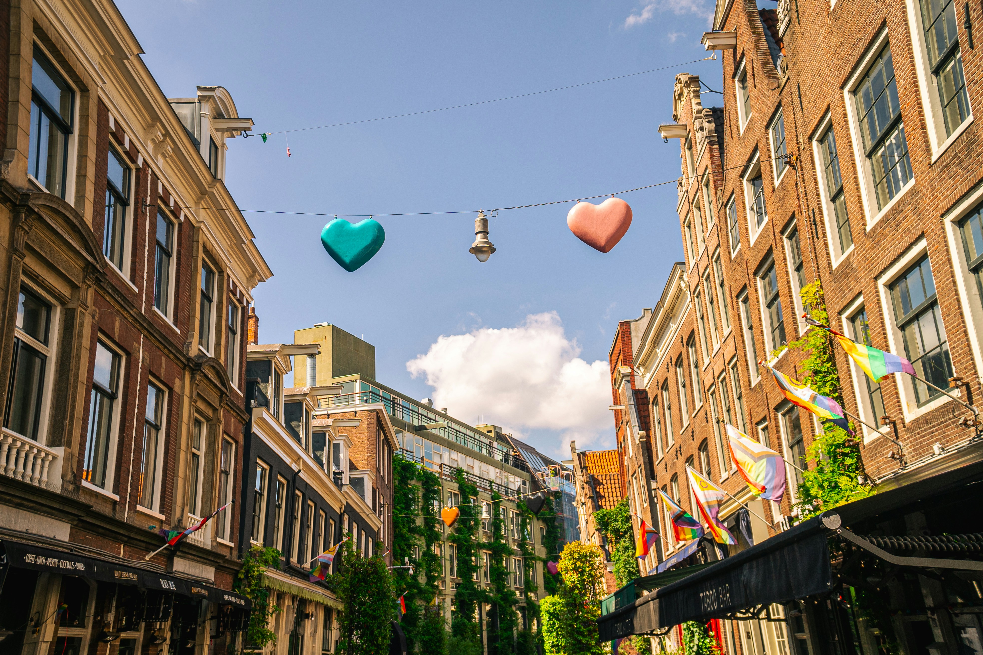 Teal and Coral Hearts Hover Over a Sunlit European Street