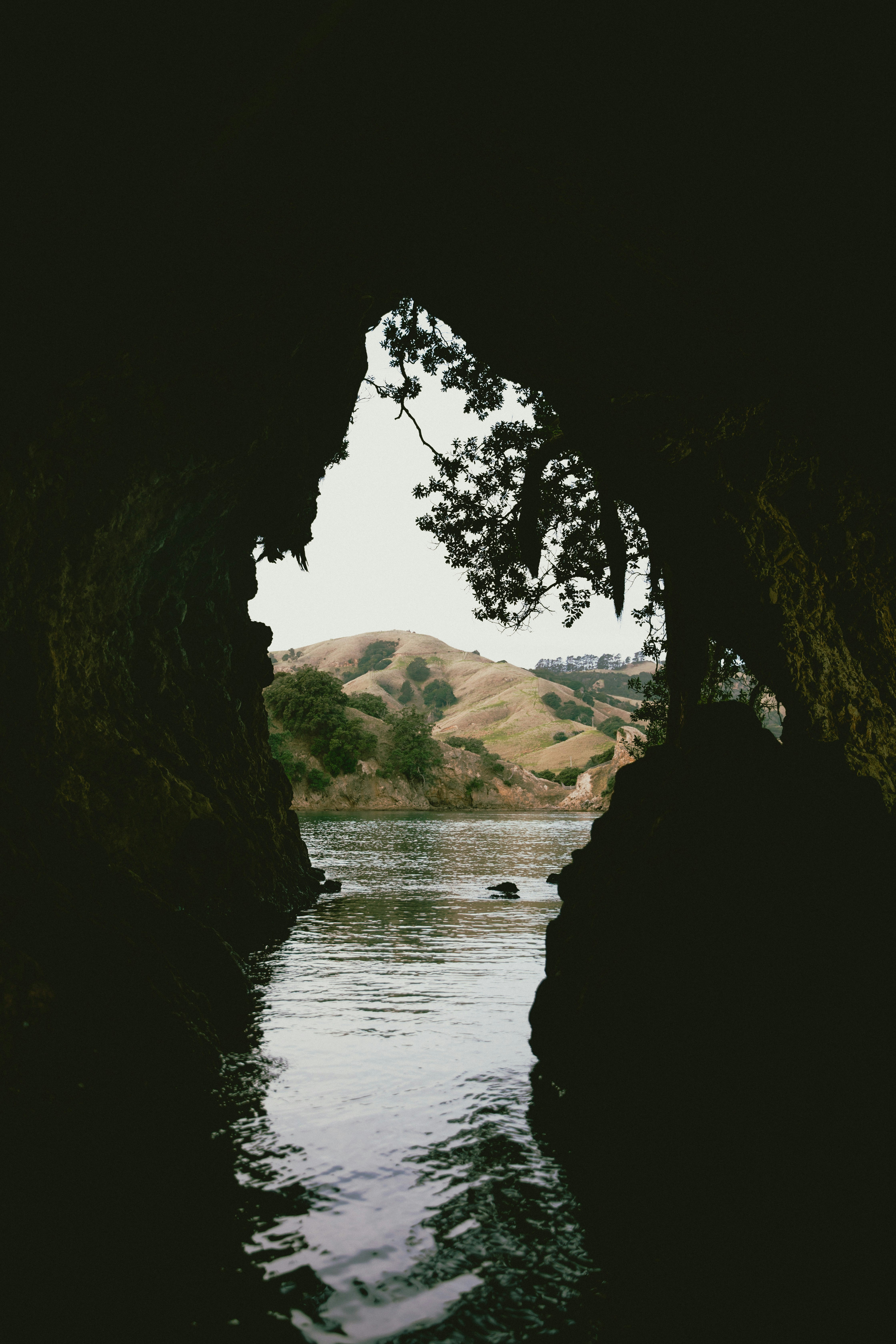 Gate to Light: A Cave Opening Framing Hills and Quiet Water