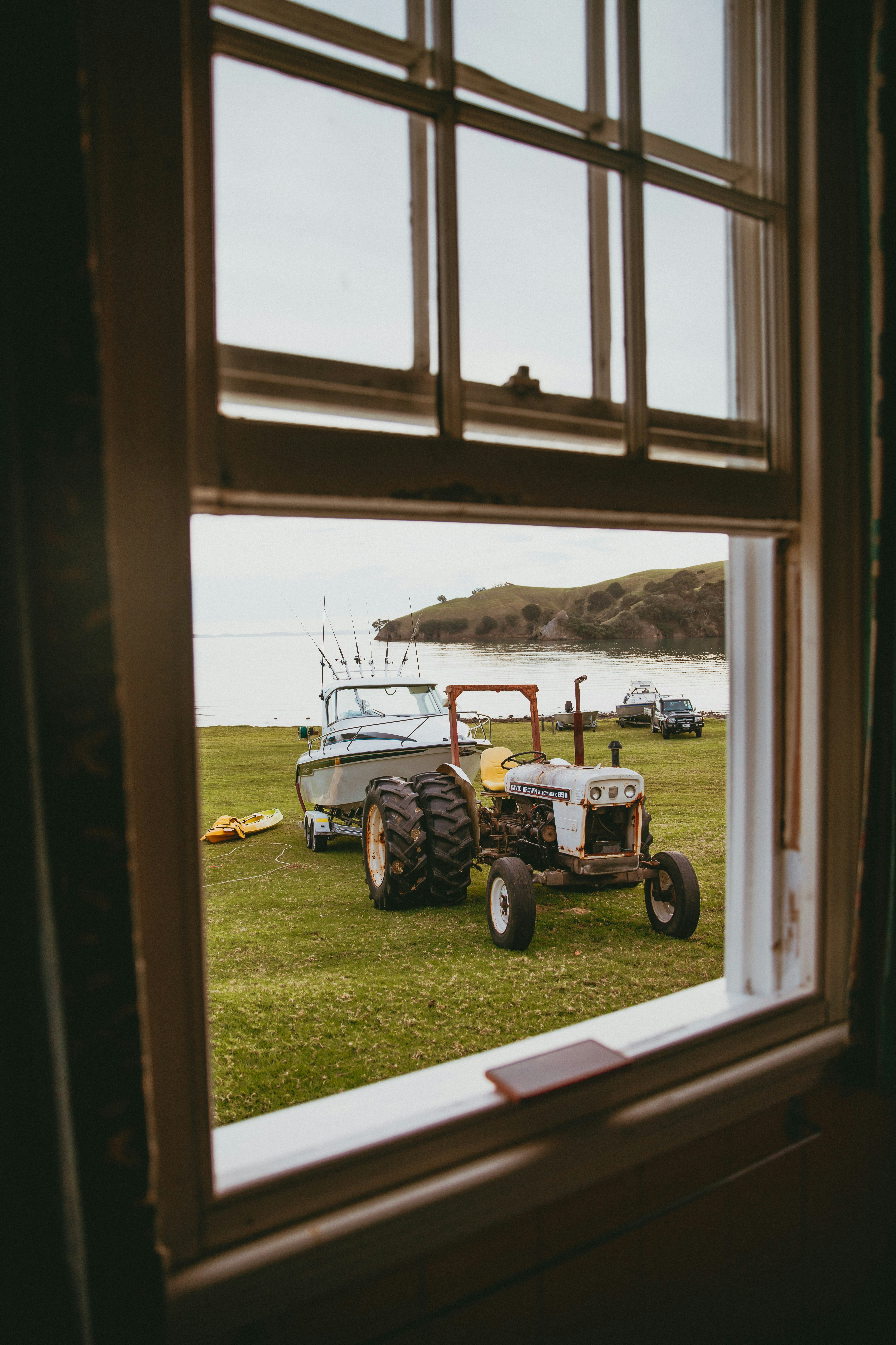 A tractor is parked in a field behind a window photo – Free Te kouma ...