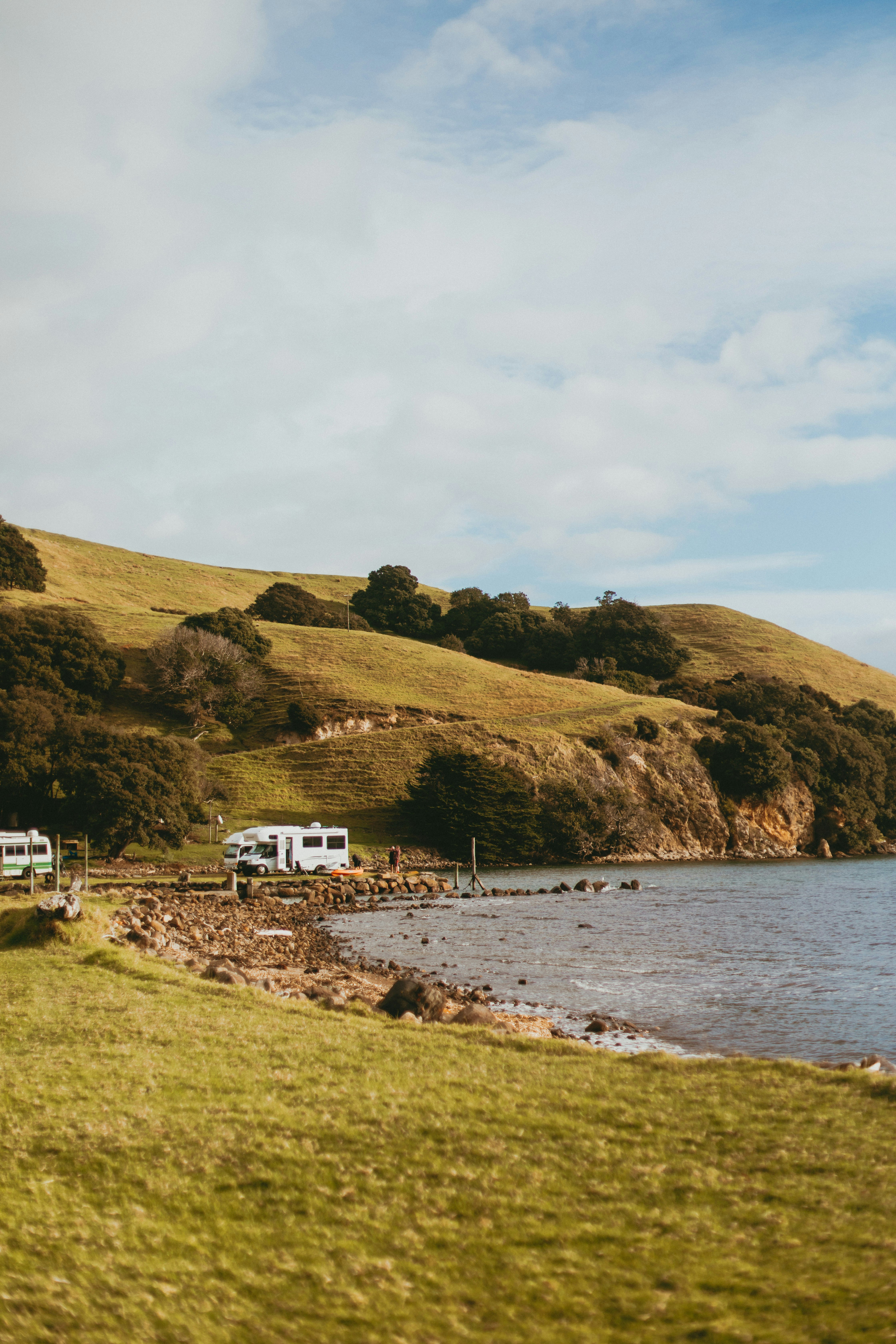 Caravan by the Shoreline: Golden Hills and Calm Waters