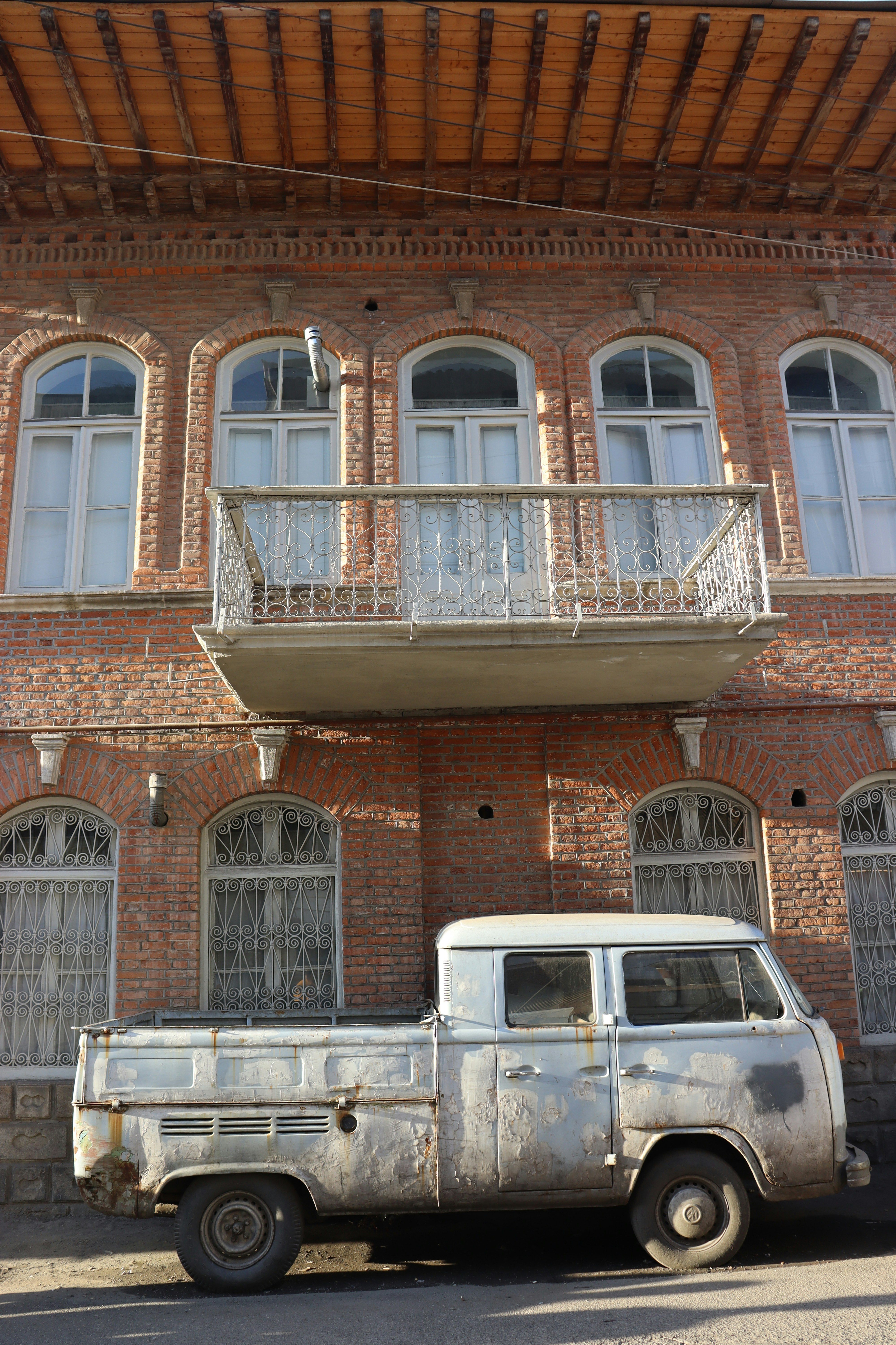 Perched on Brick: A Bird Over a Weathered Pickup