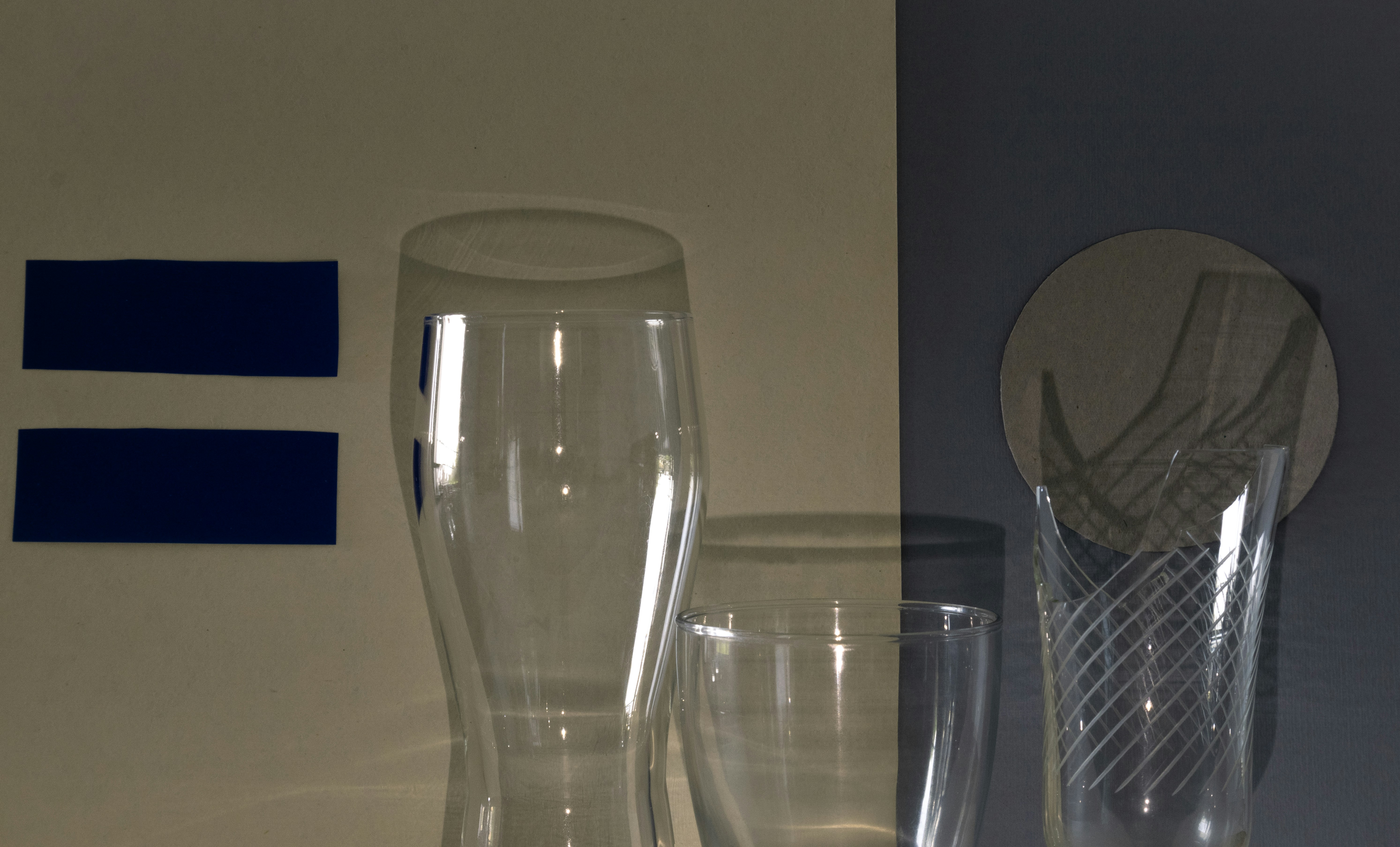 Transparent glassware casting intricate shadows on a textured surface.