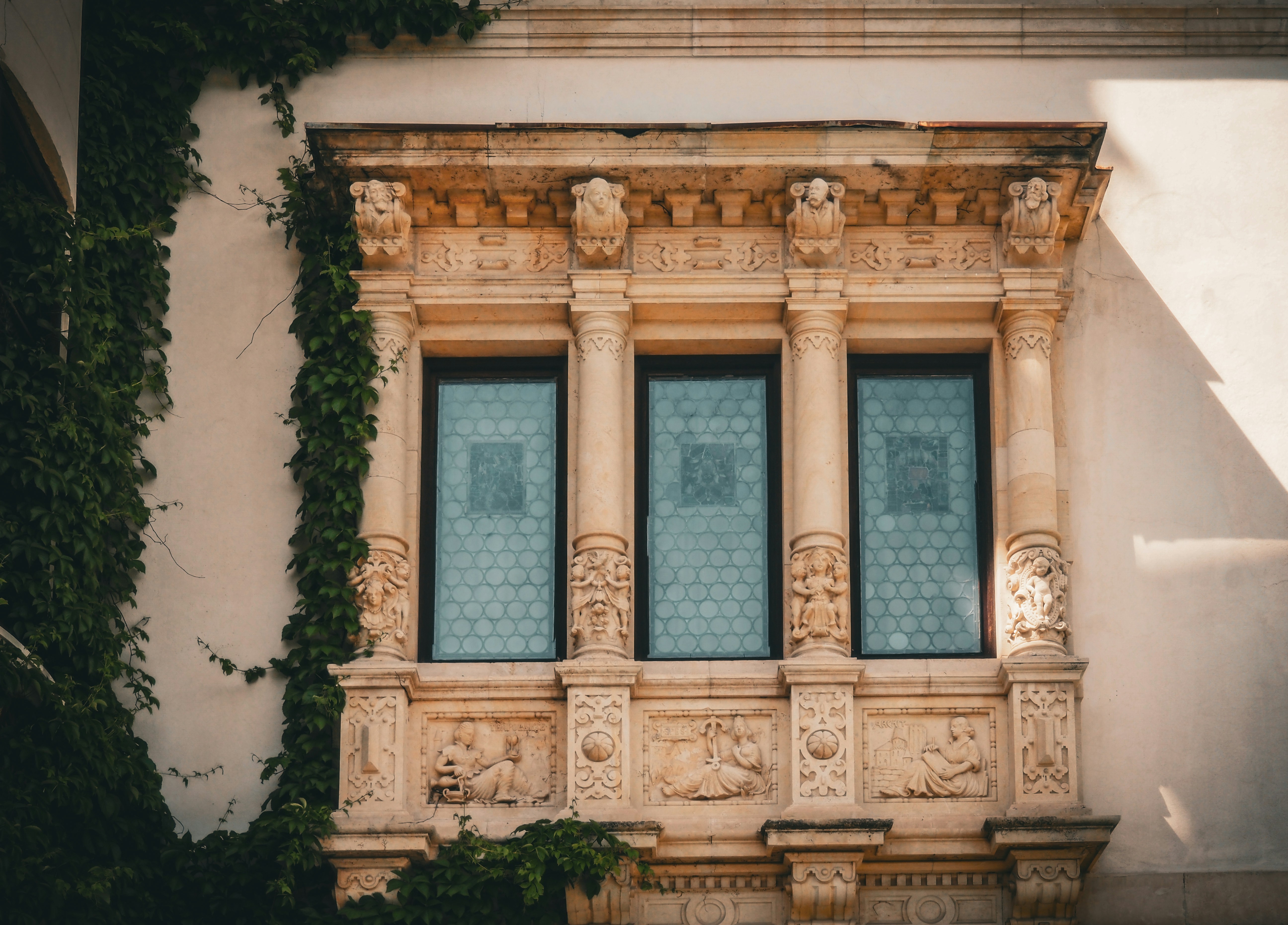 Ivied Carved Window Frieze on a Sunlit Facade
