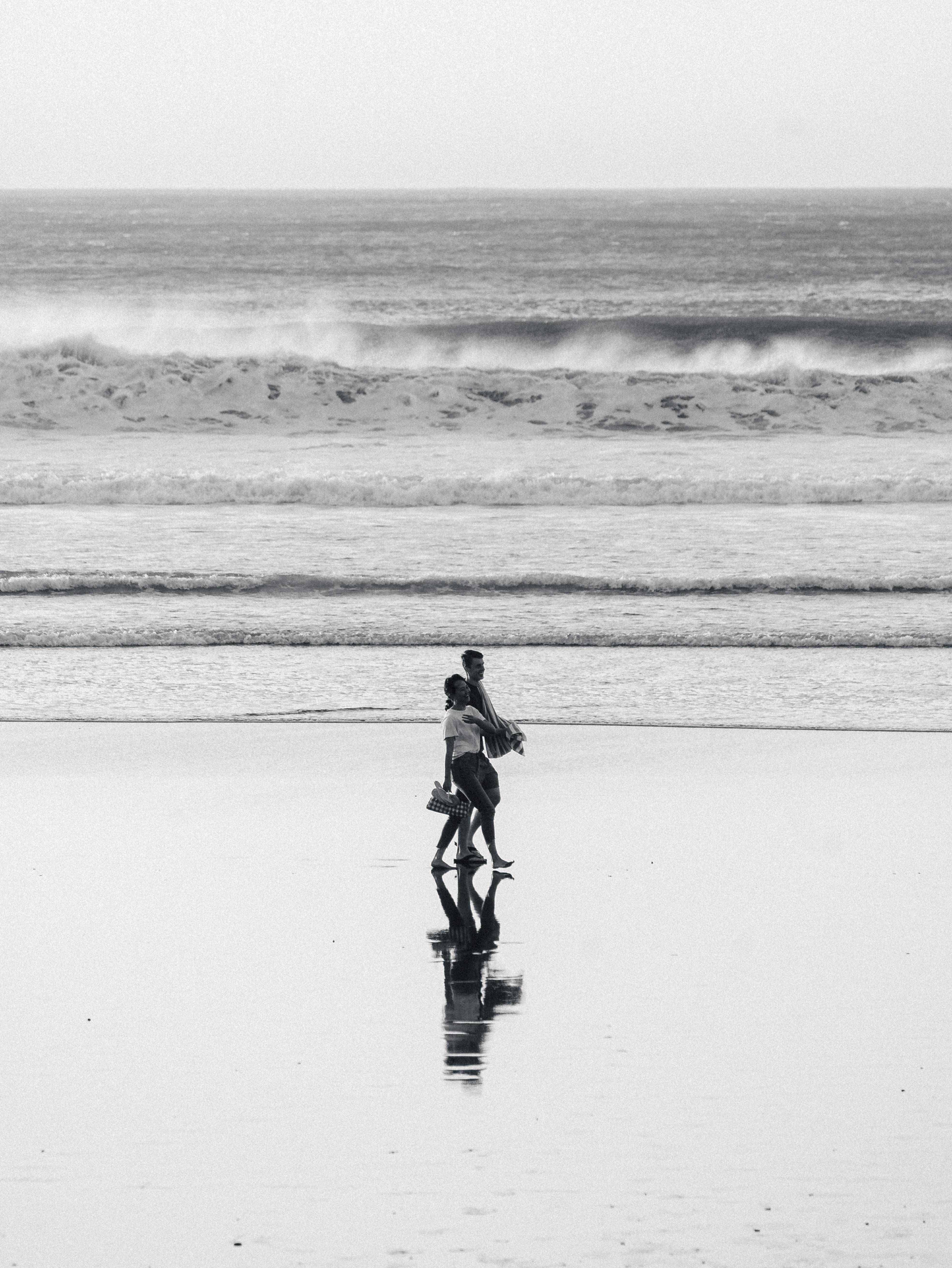 Duet on the Glassy Shore: Silhouettes Crossing the Wet Sand