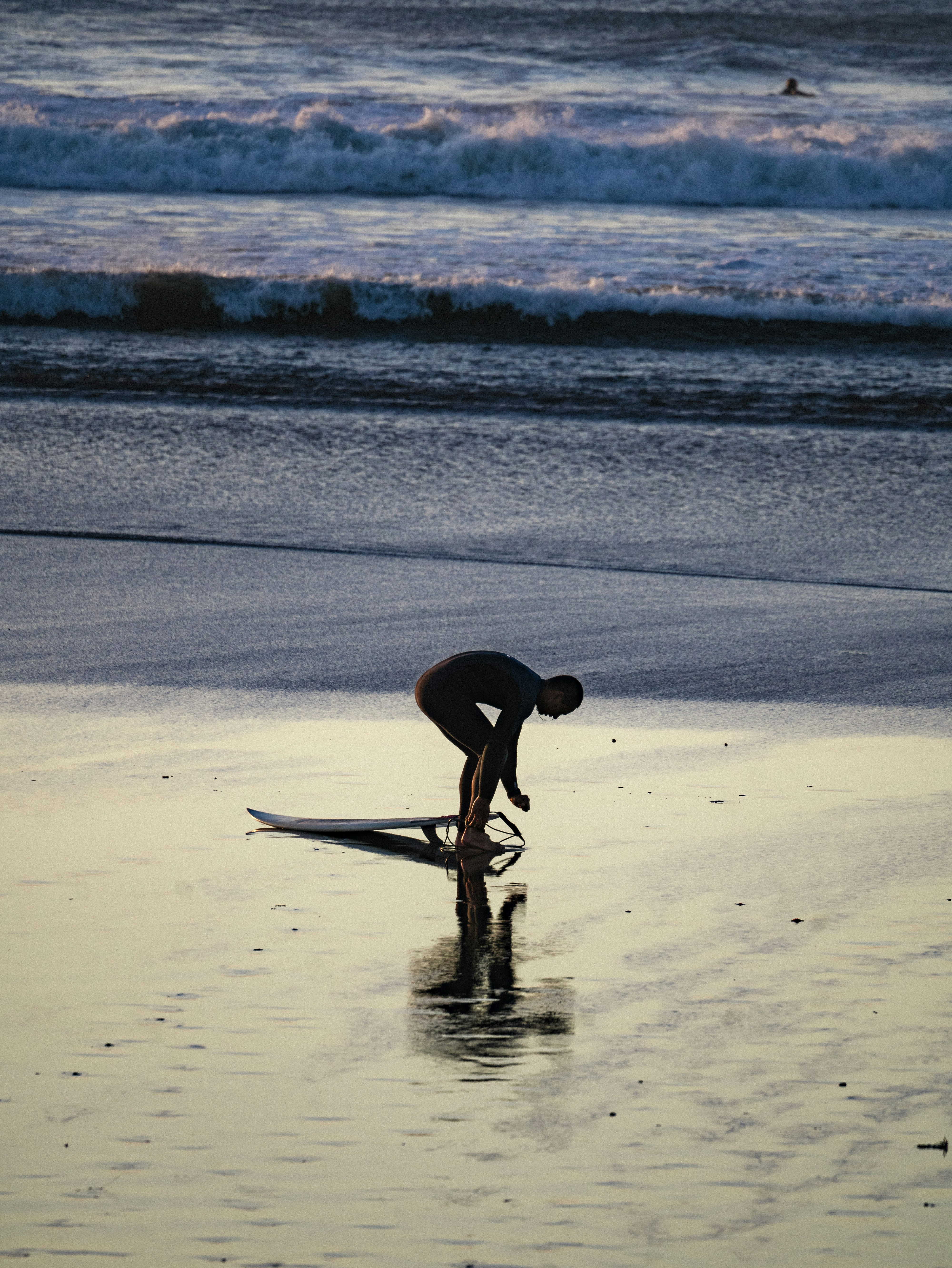 Dusk on a Glassy Shore: Surfer Aligns the Board
