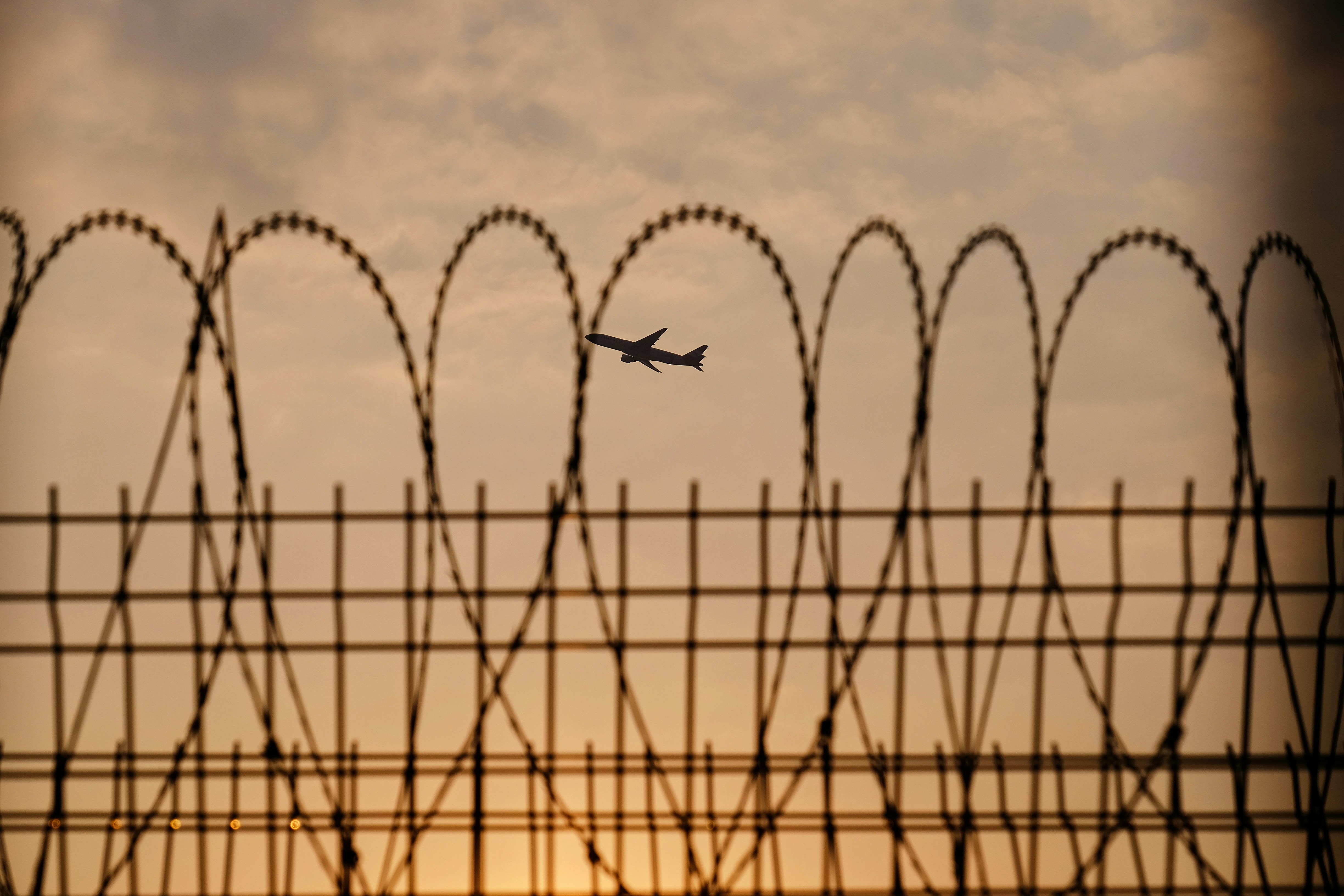 A plane flying over a barbed wire fence photo – Free Airport Image on ...