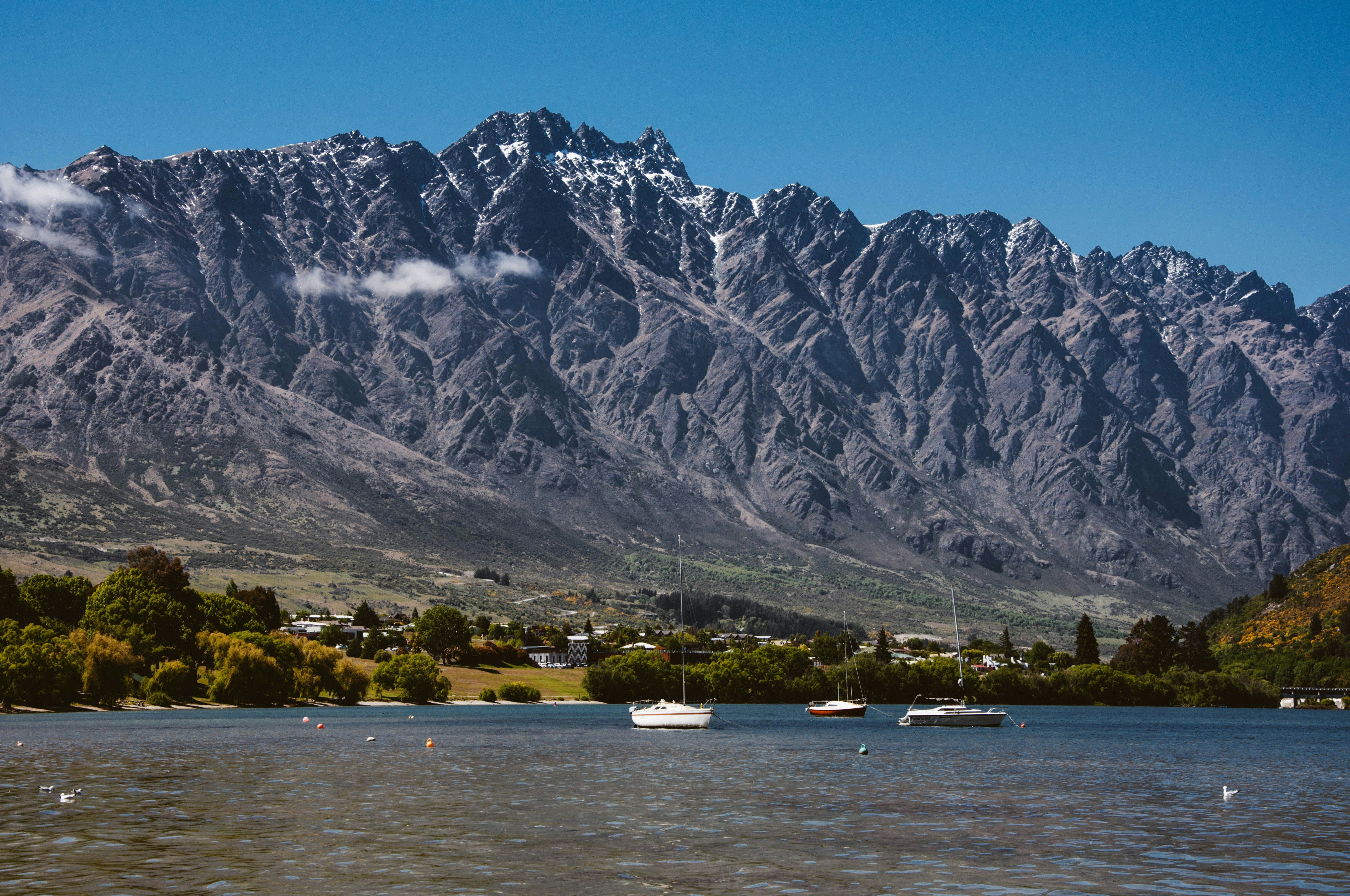A lake with boats floating on it and a mountain in the background photo ...