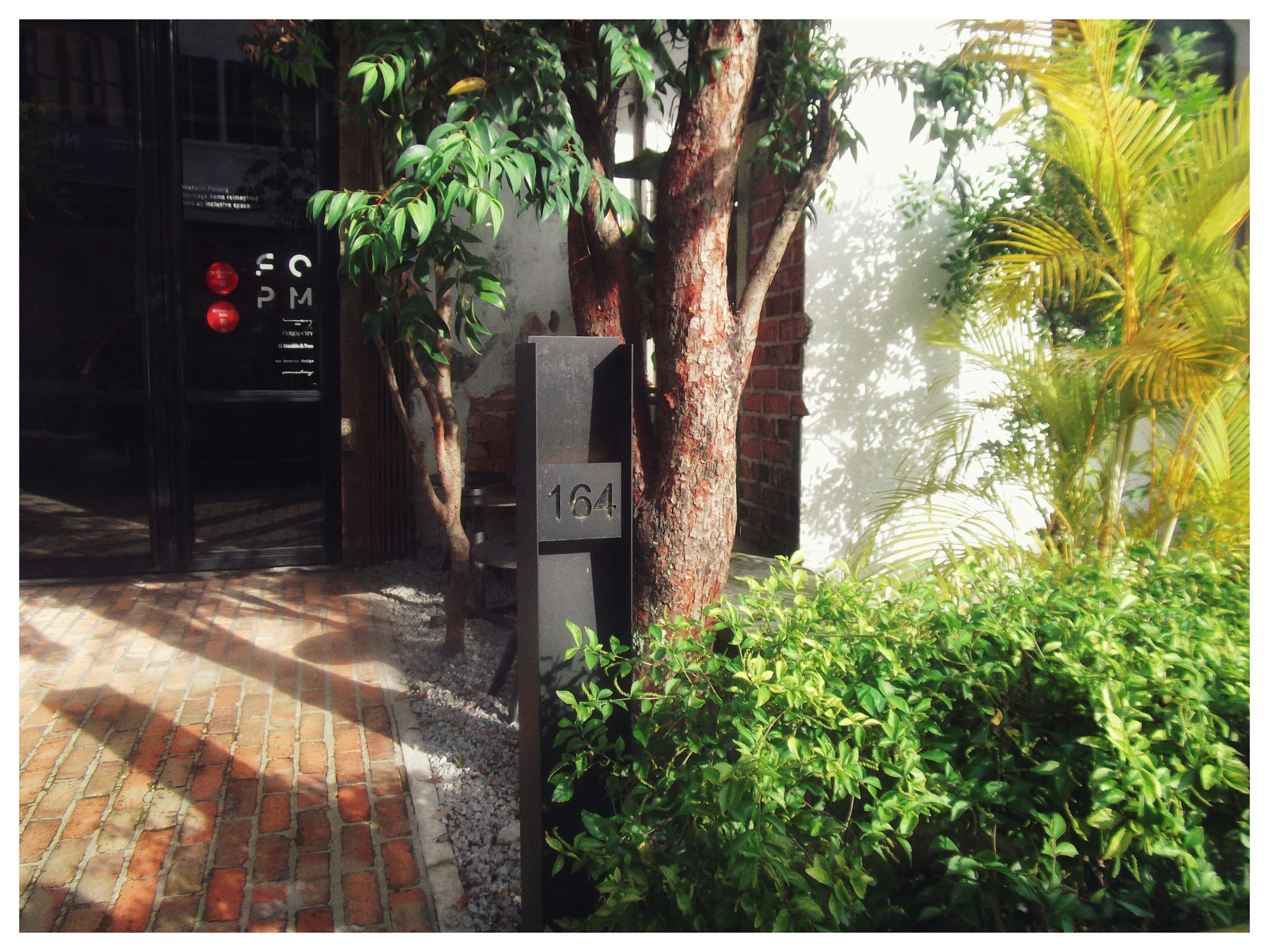 164 Post at the Sunlit Entrance: Brick Pathway Framed by Greenery