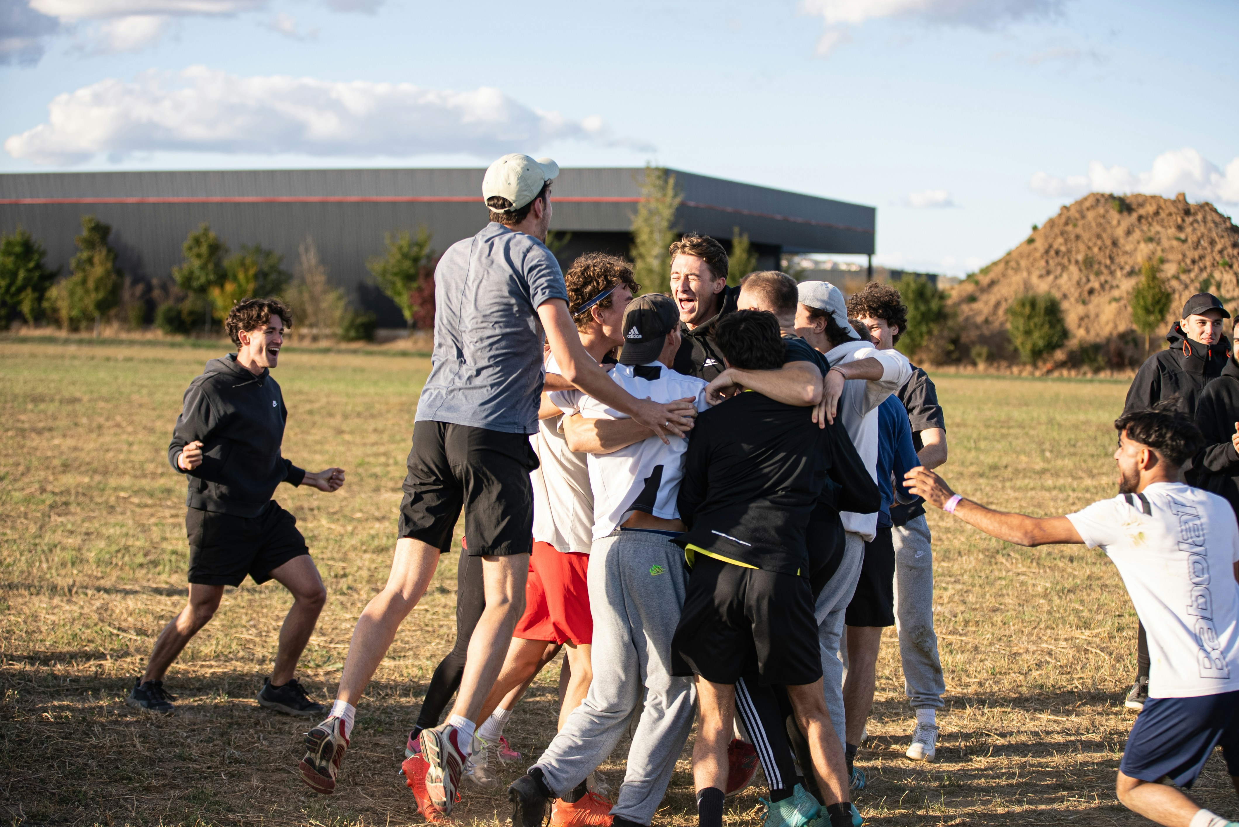 A group of people are huddled together in a field photo – Free Man ...