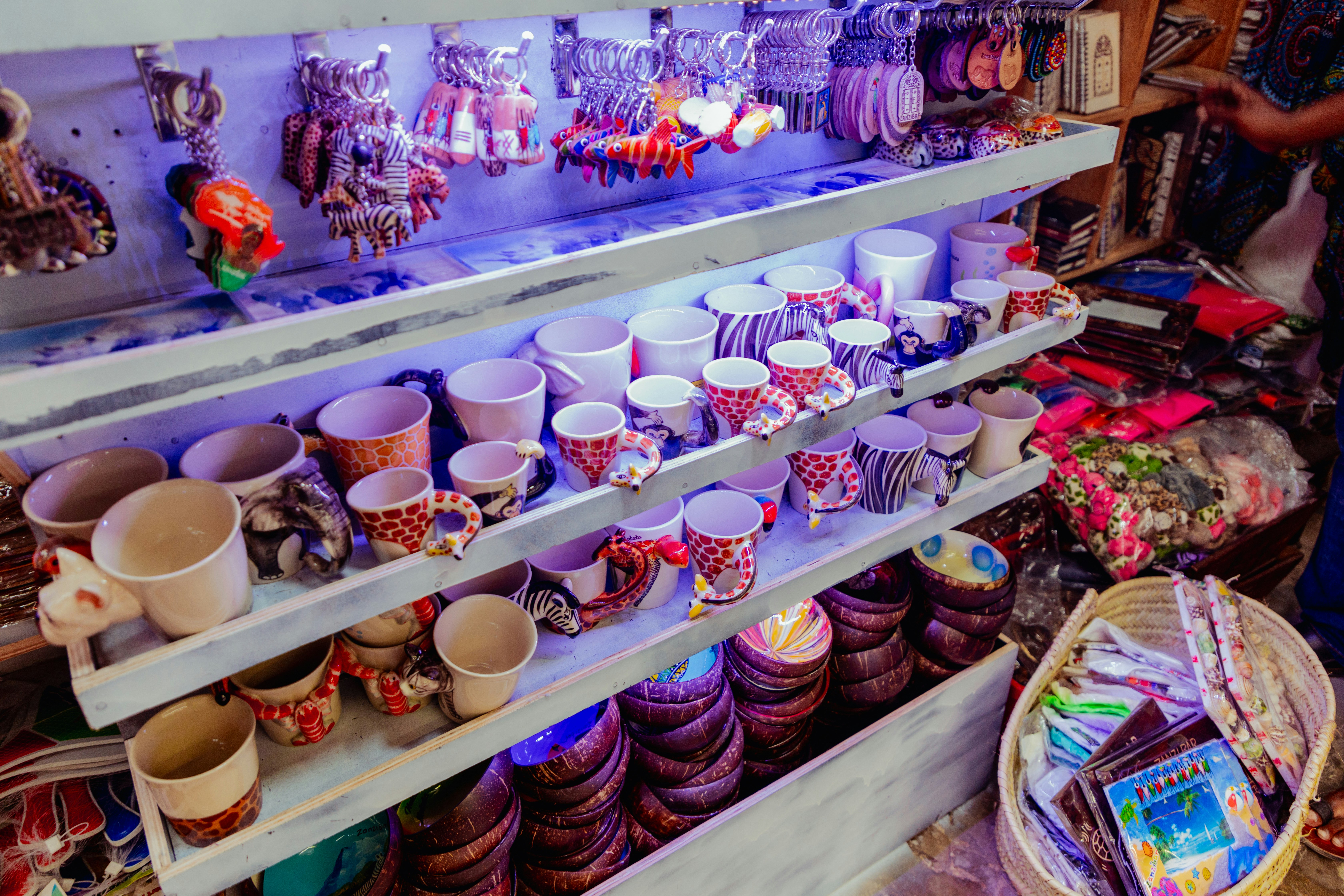 Colorful Mug Rows Beneath a Jewelry-Decorated Shelf in a Busy Market Stall