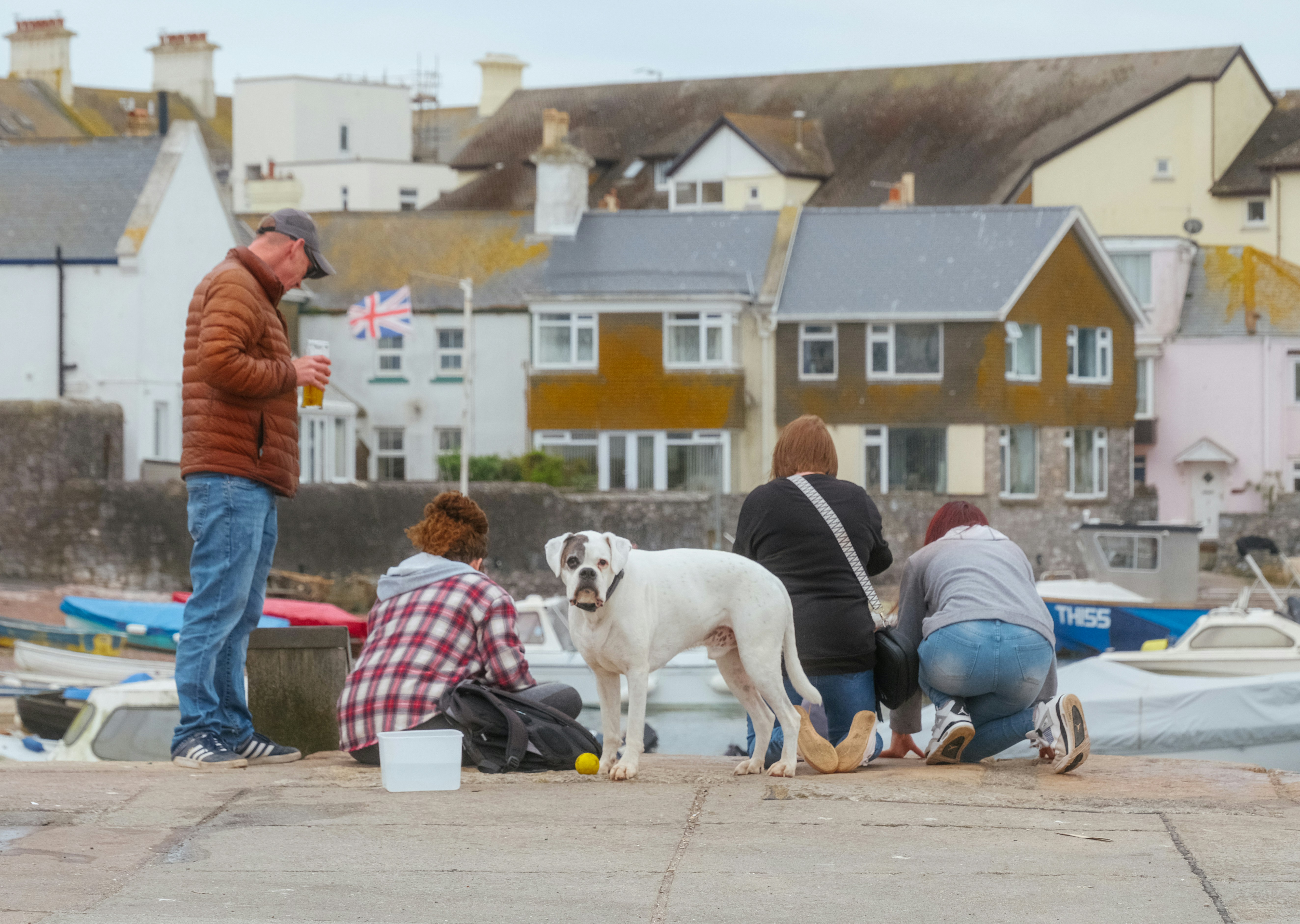 Couldnt' work out if he wanted to kill us or for us to throw the ball... | a group of people sitting on a dock with a dog