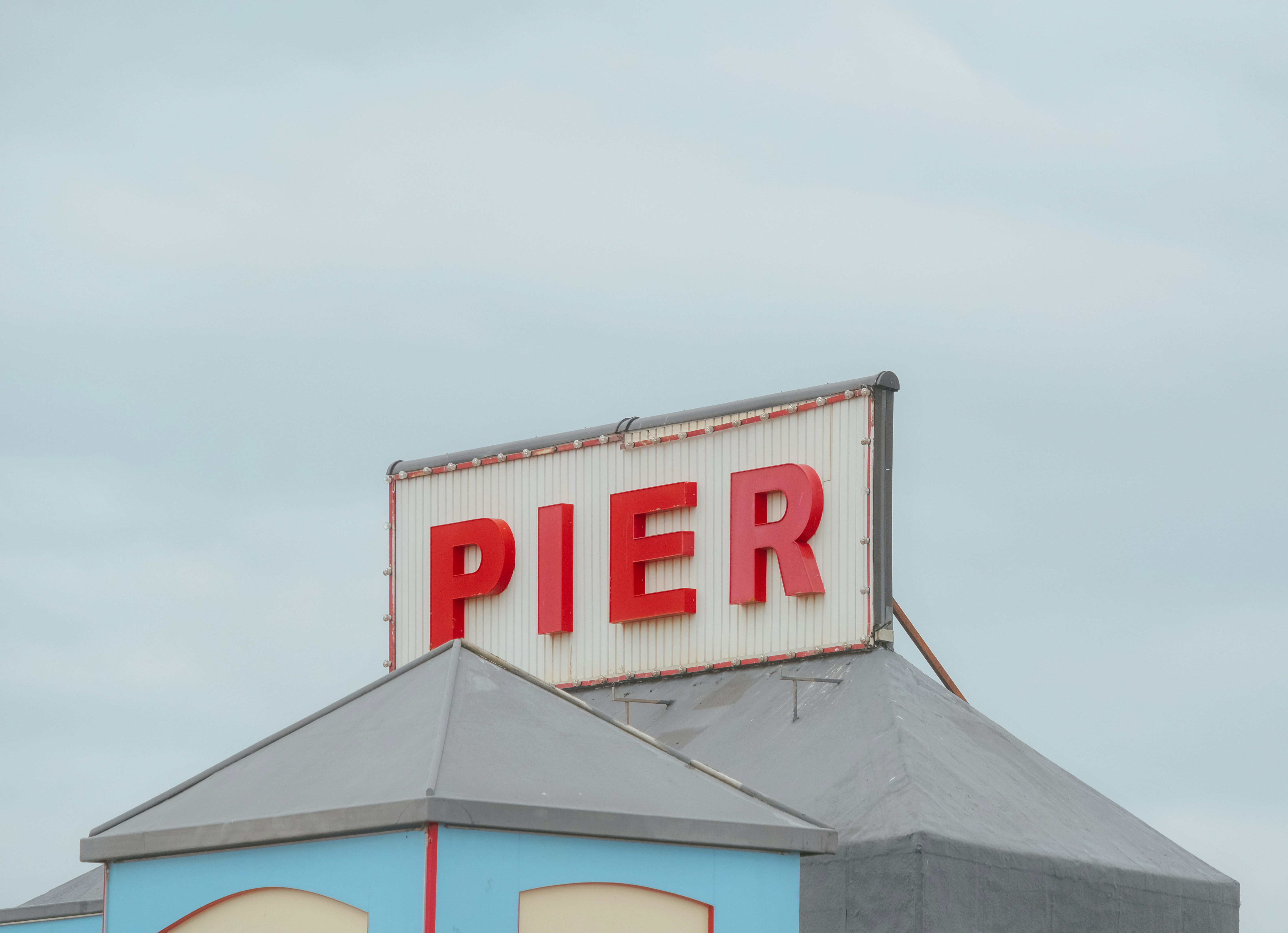 PIER Signover: A glimpse of a seaside beacon above colorful kiosk rooftops