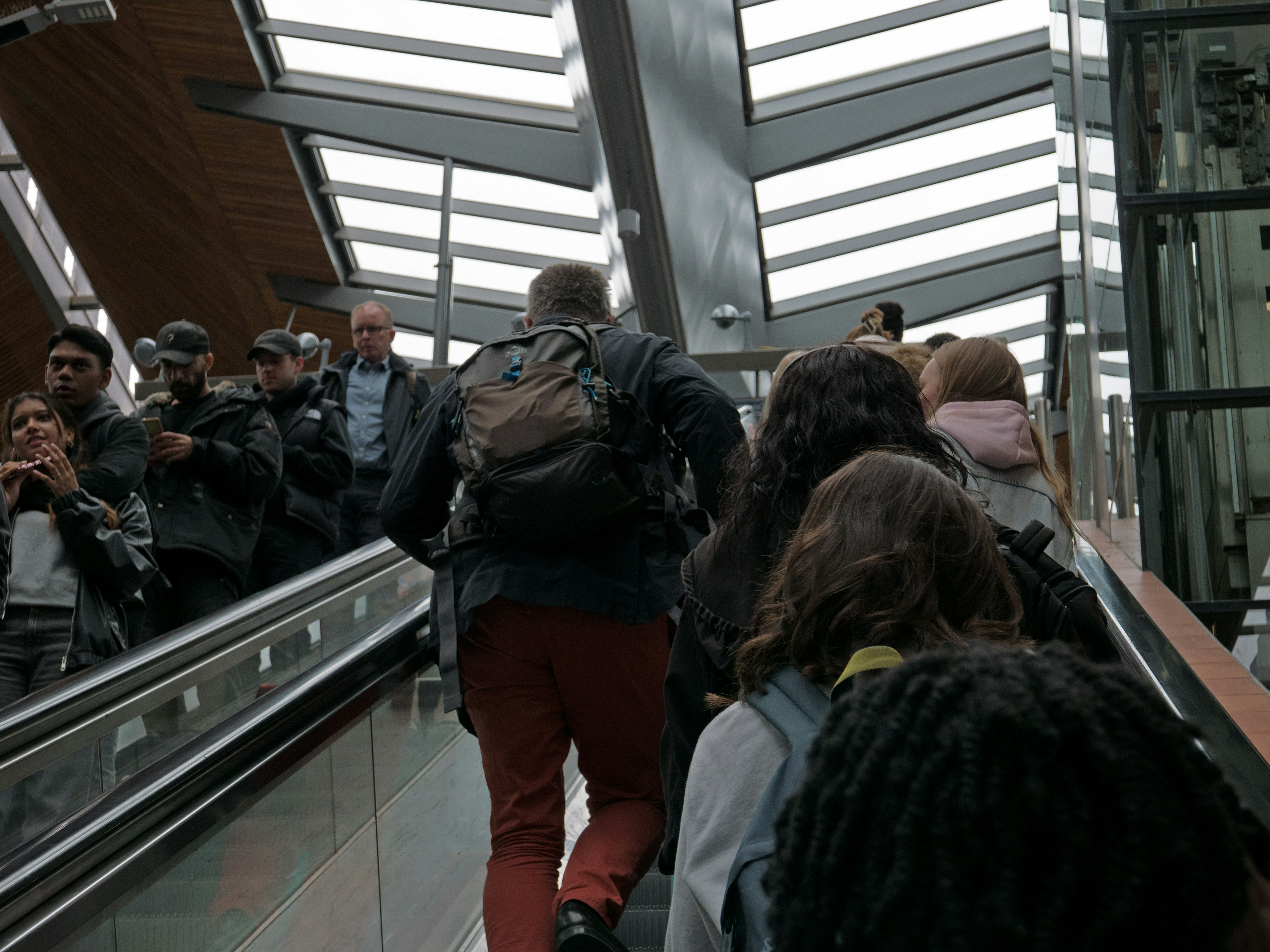Crimson Pants on the Ascent: A Crowd Beneath Glass and Steel