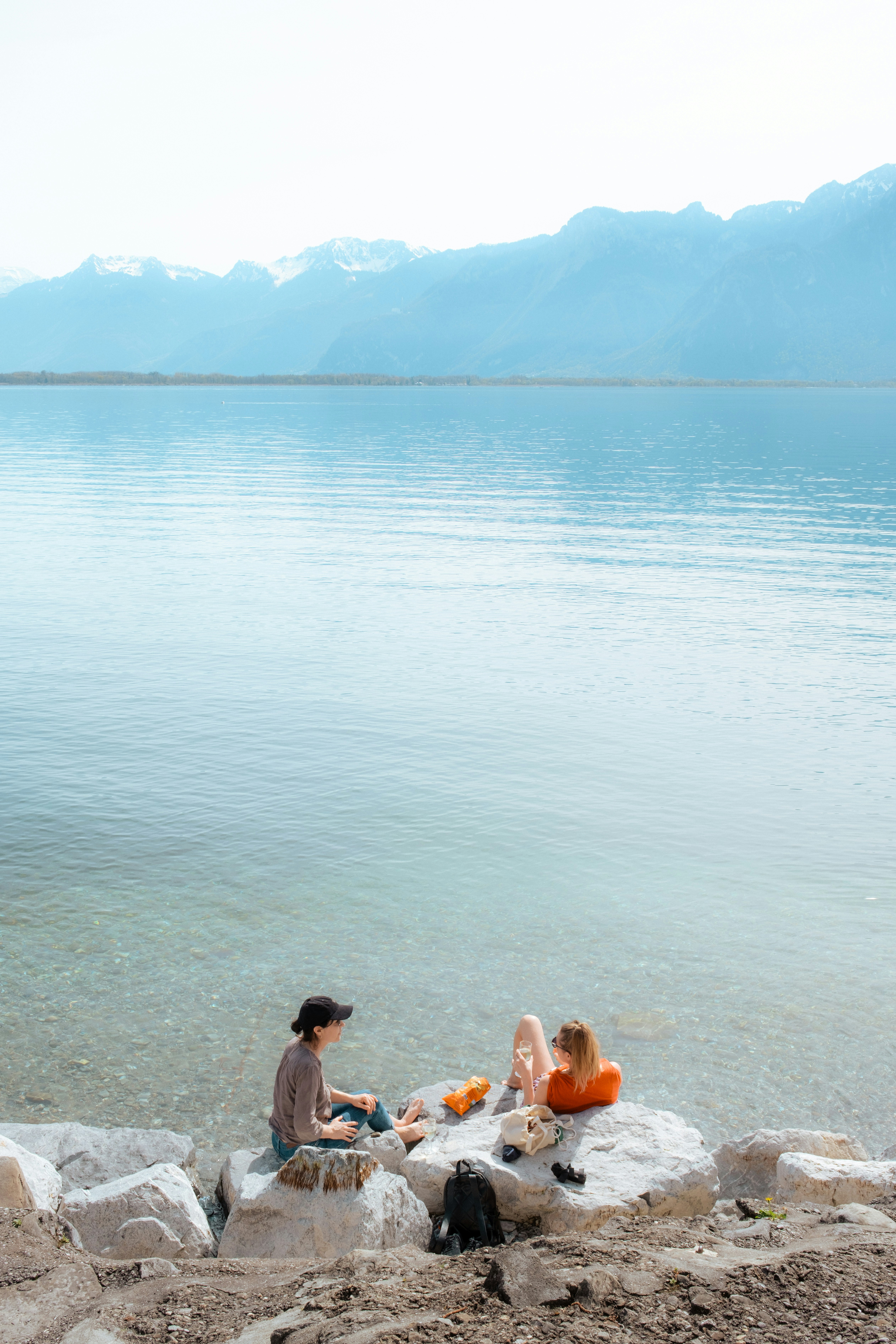 A group of people sitting on rocks near the water photo – Free Blue ...