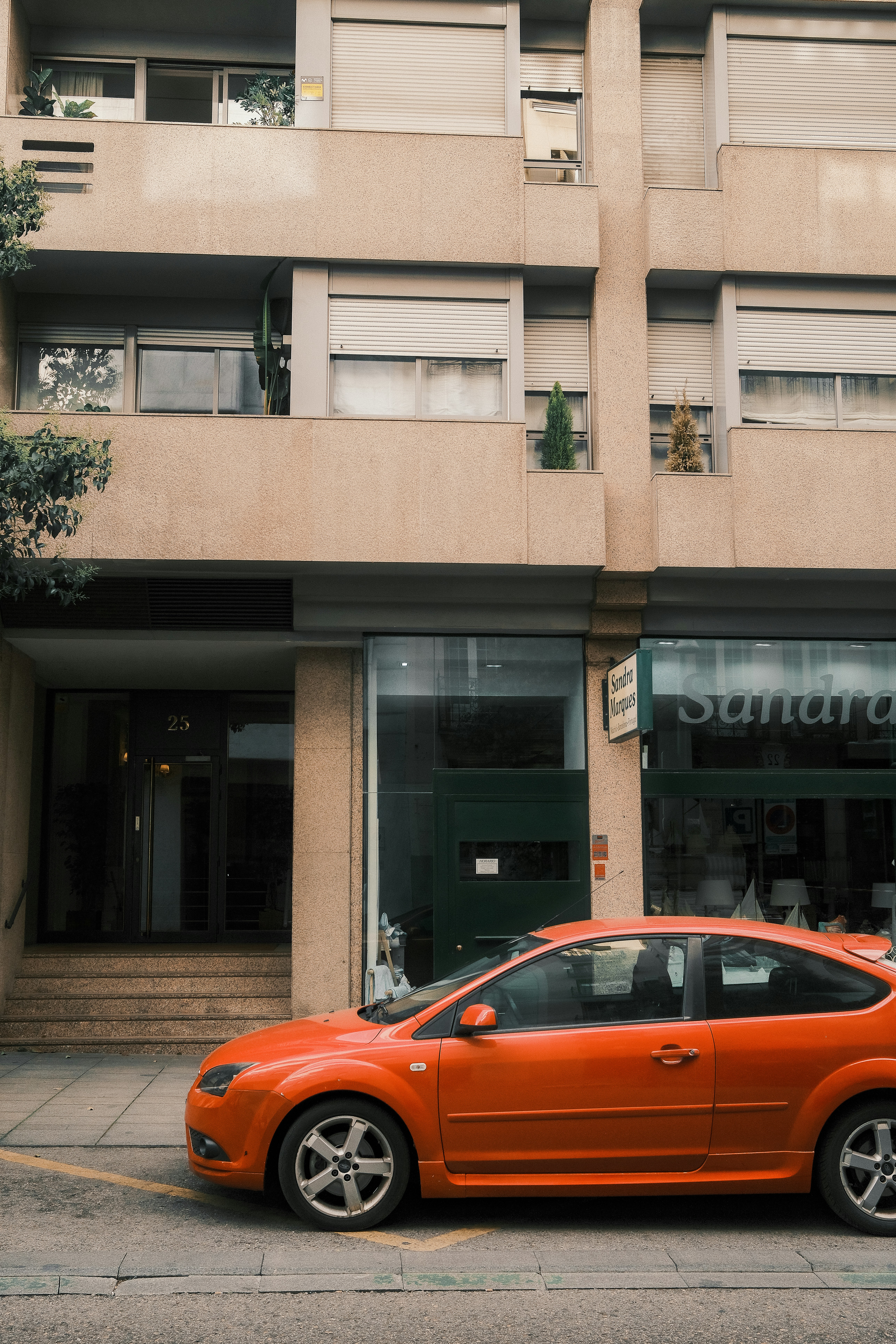 Orange sedan aligns with urban concrete: a quiet street level portrait
