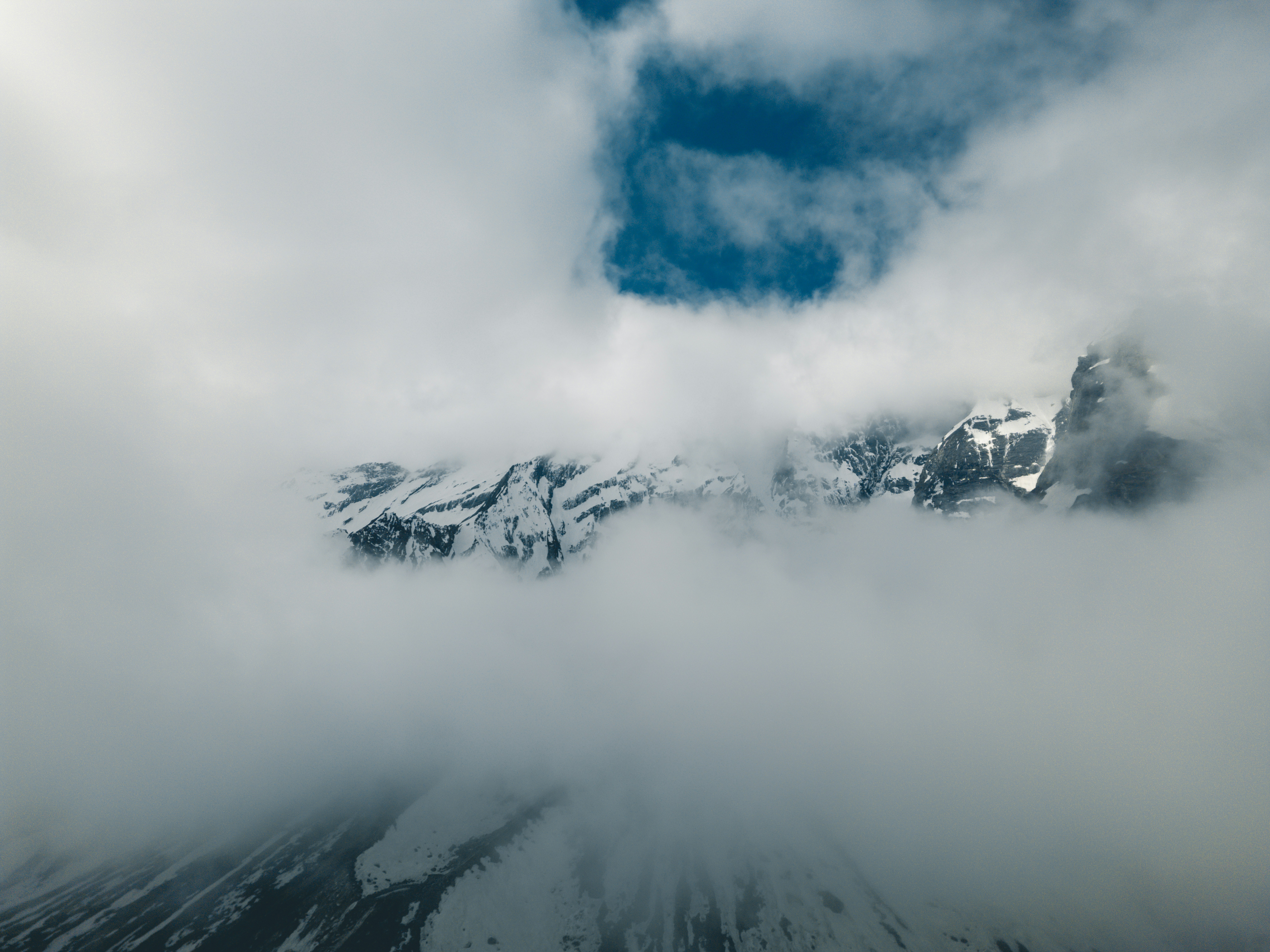 A mountain covered in snow and clouds under a blue sky photo – Free ...