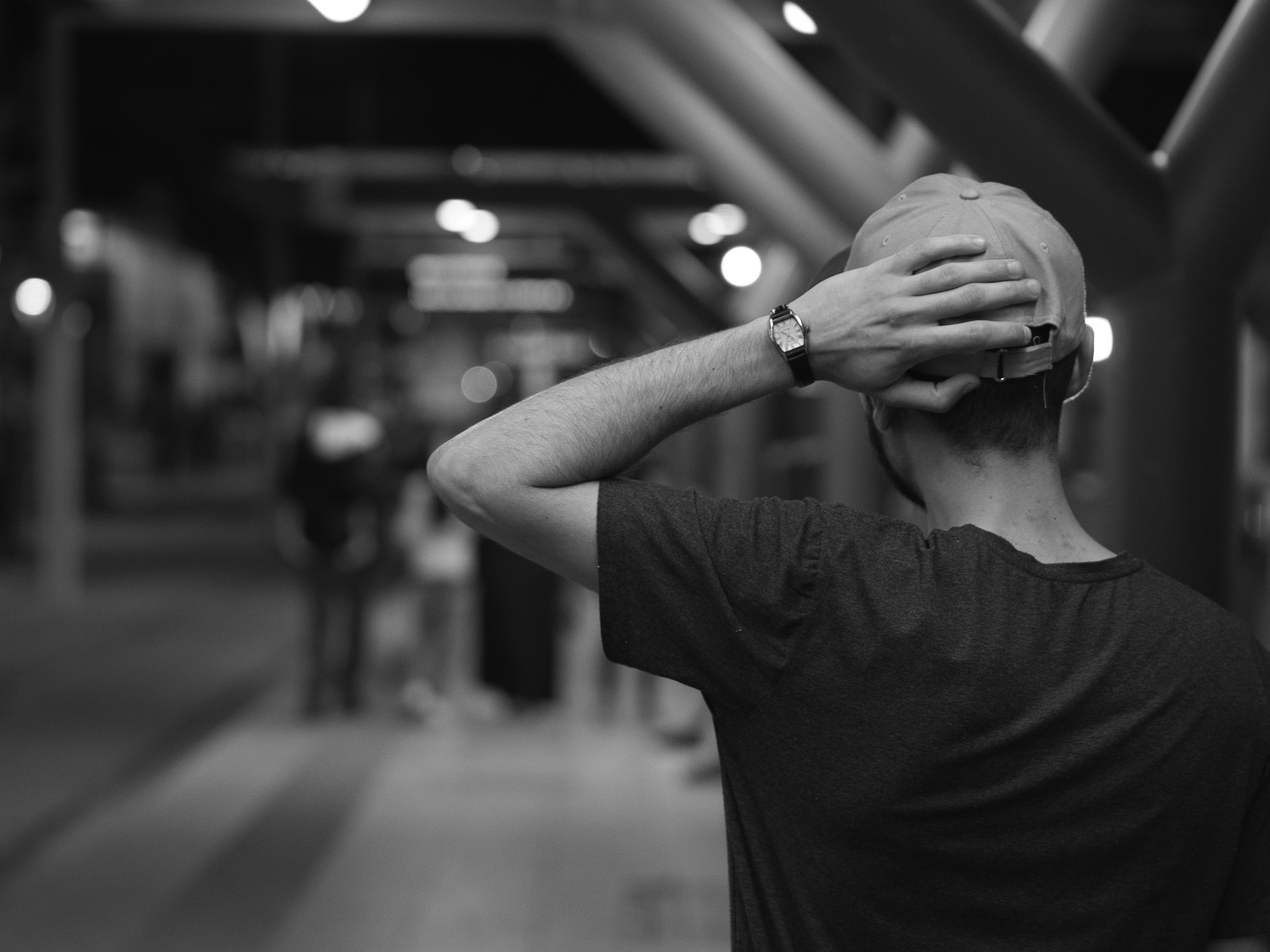Cap in Hand: A Quiet Portrait in a Dim Transit Hall