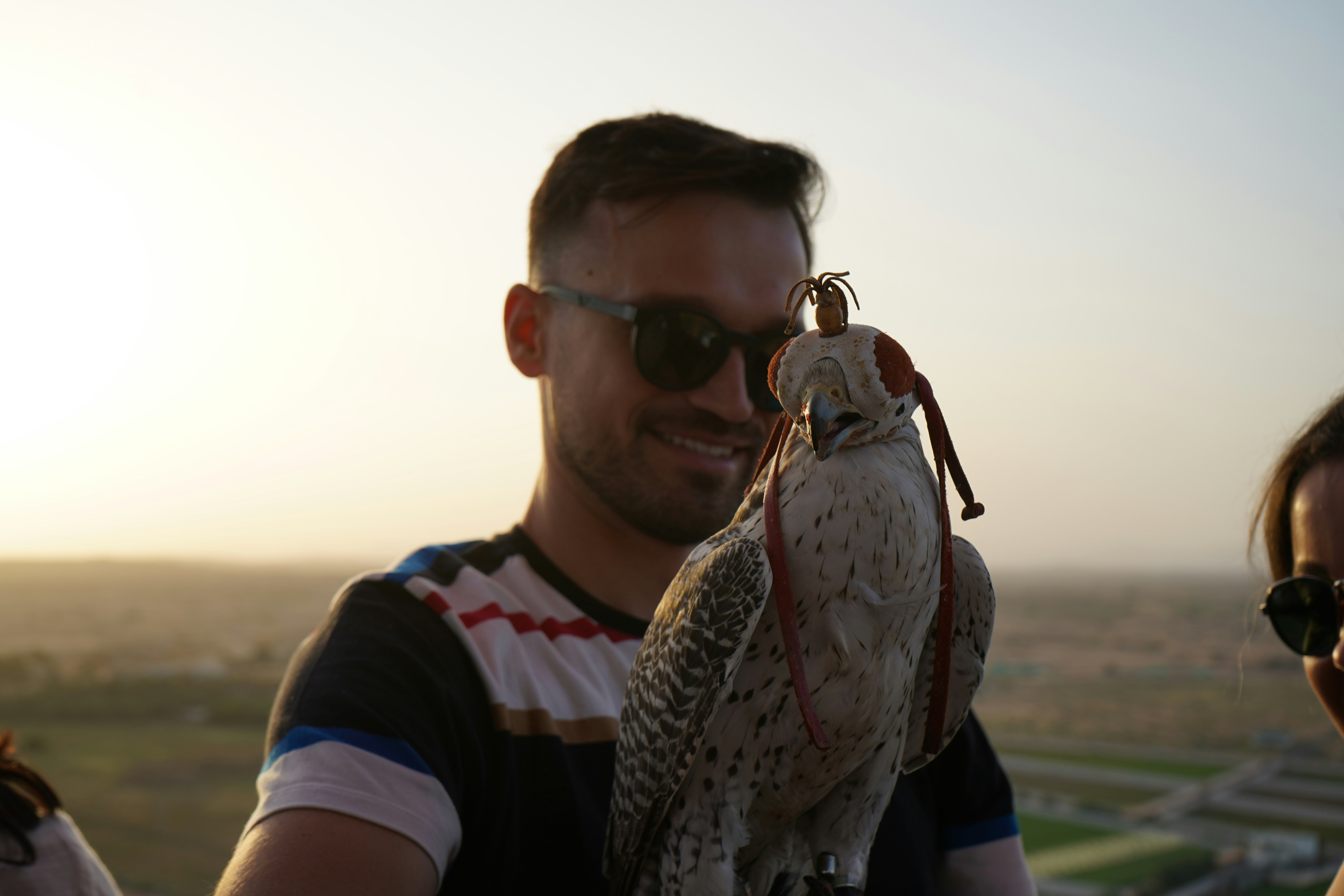 Man smiling with hooded falcon perched on hand