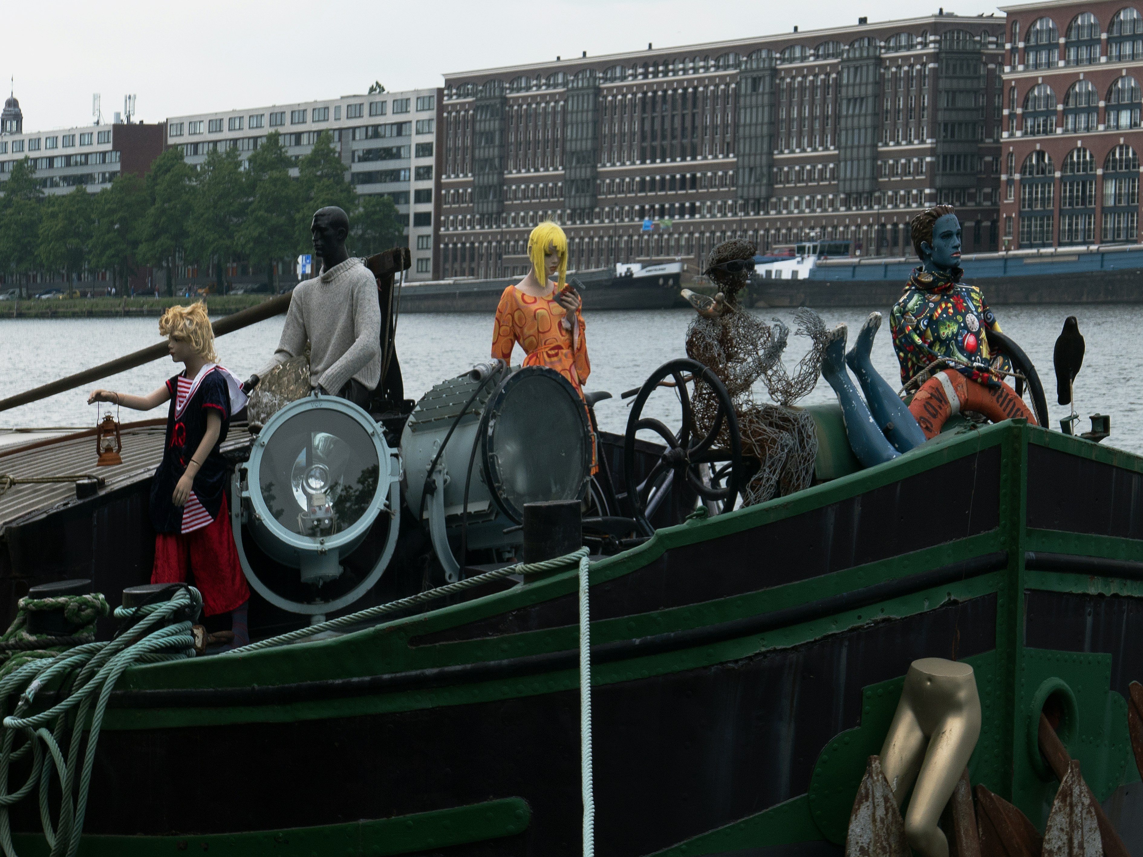 Free photo, group of mannequin dolls on an old houseboat, in the old harbour IJhaven in Amsterdam city. In the background brick facades of former store houses at the street Veemkade. The ship is parked along the street of Java eiland. Every month the show changes here with other dolls. Urban street photography in free download images for poster or wallpaper, photos of cities in The Netherlands by Fons Heijnsbroek. / Gratis foto, vrachtschip omgebouwd tot woonboot aan de Javakade, Amsterdam met aangeklede poppen. Gratis download foto - straatfotografie van stad in Nederland, Fons Heijnsbroek.