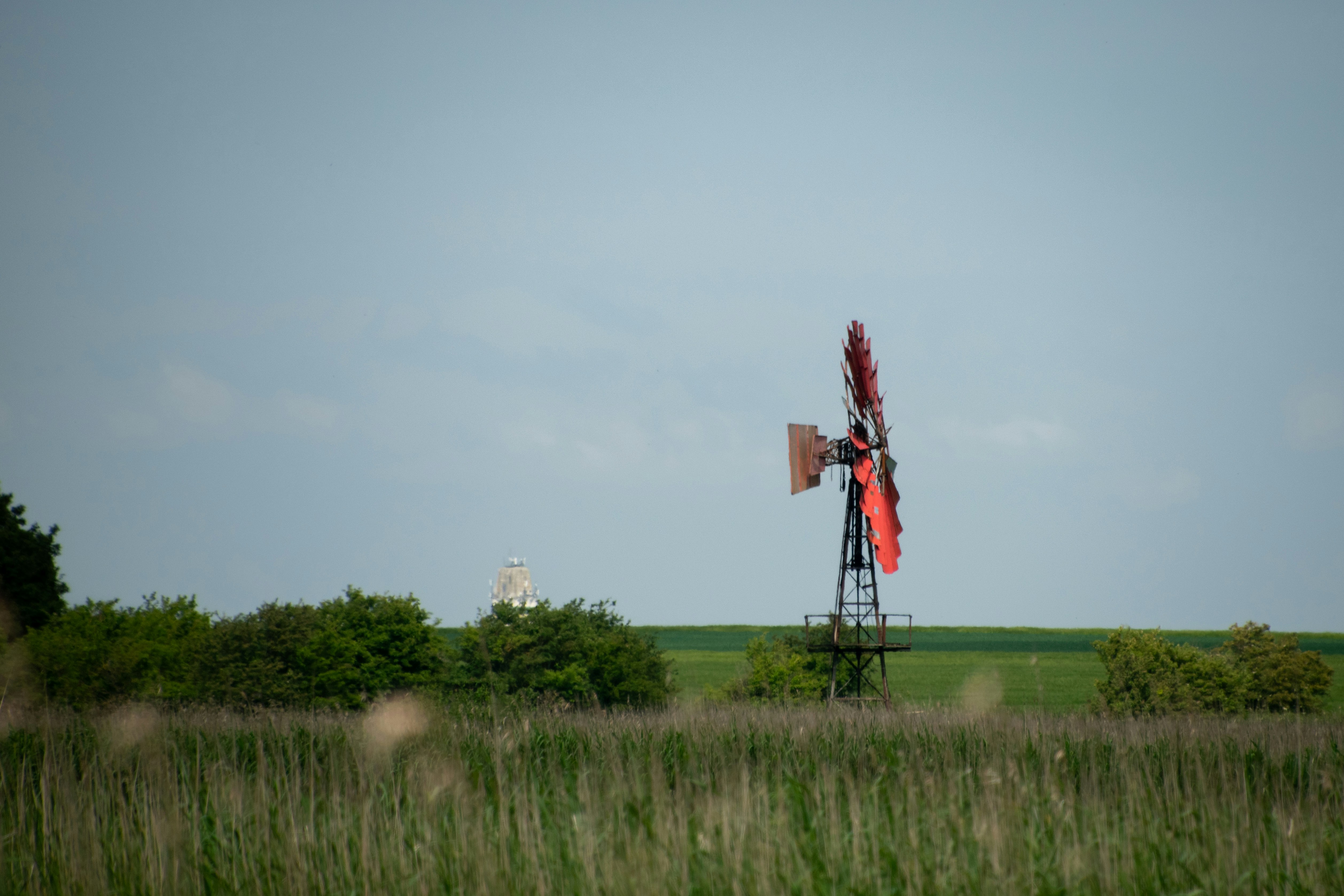 Crimson Blades over the Prairie: A solitary windmill under a pale sky