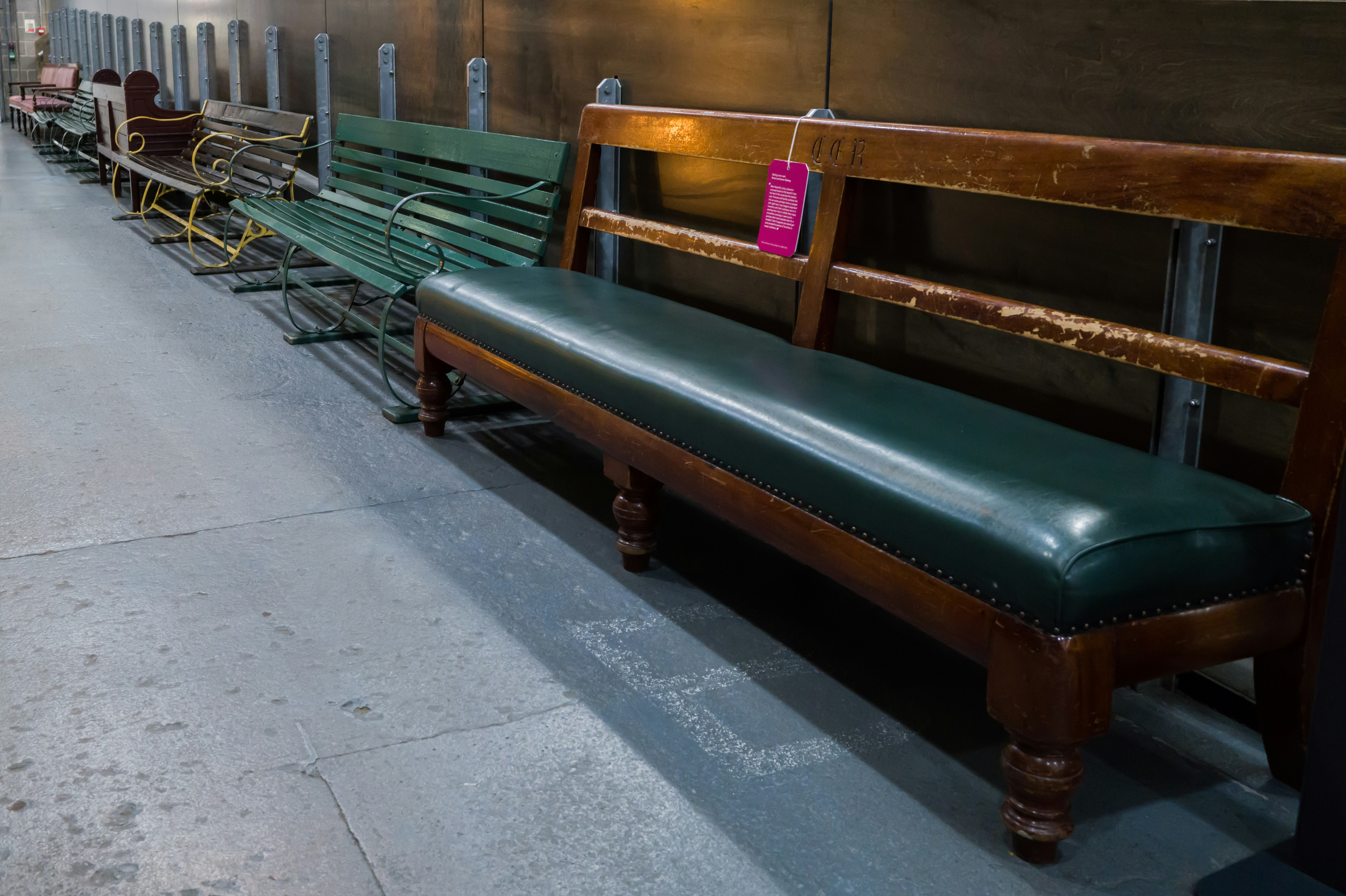 A row of green benches sitting next to each other photo – Free Museum ...