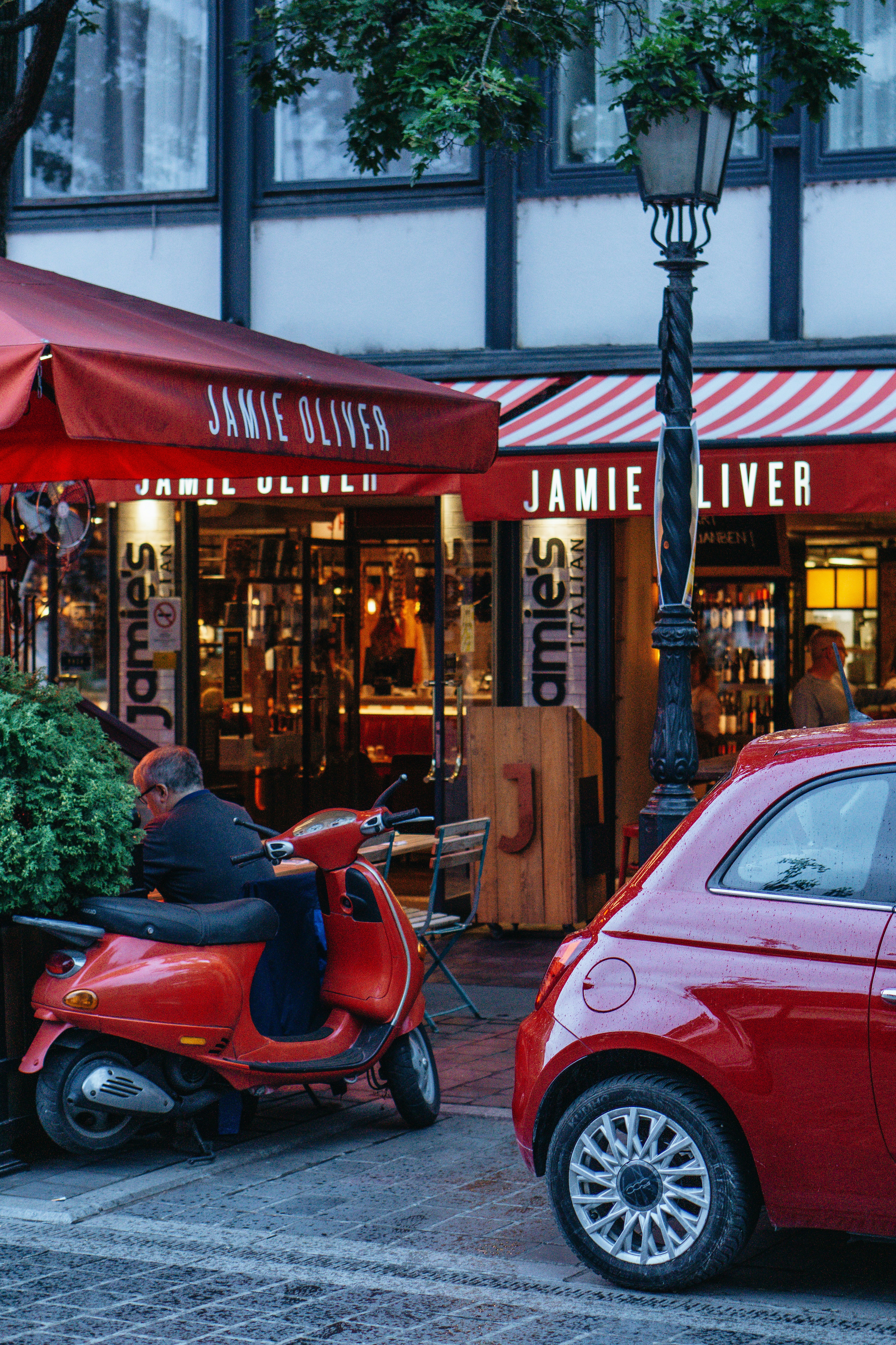 Red Scooter, Velvet Street Café, and a Glinting Car at Twilight