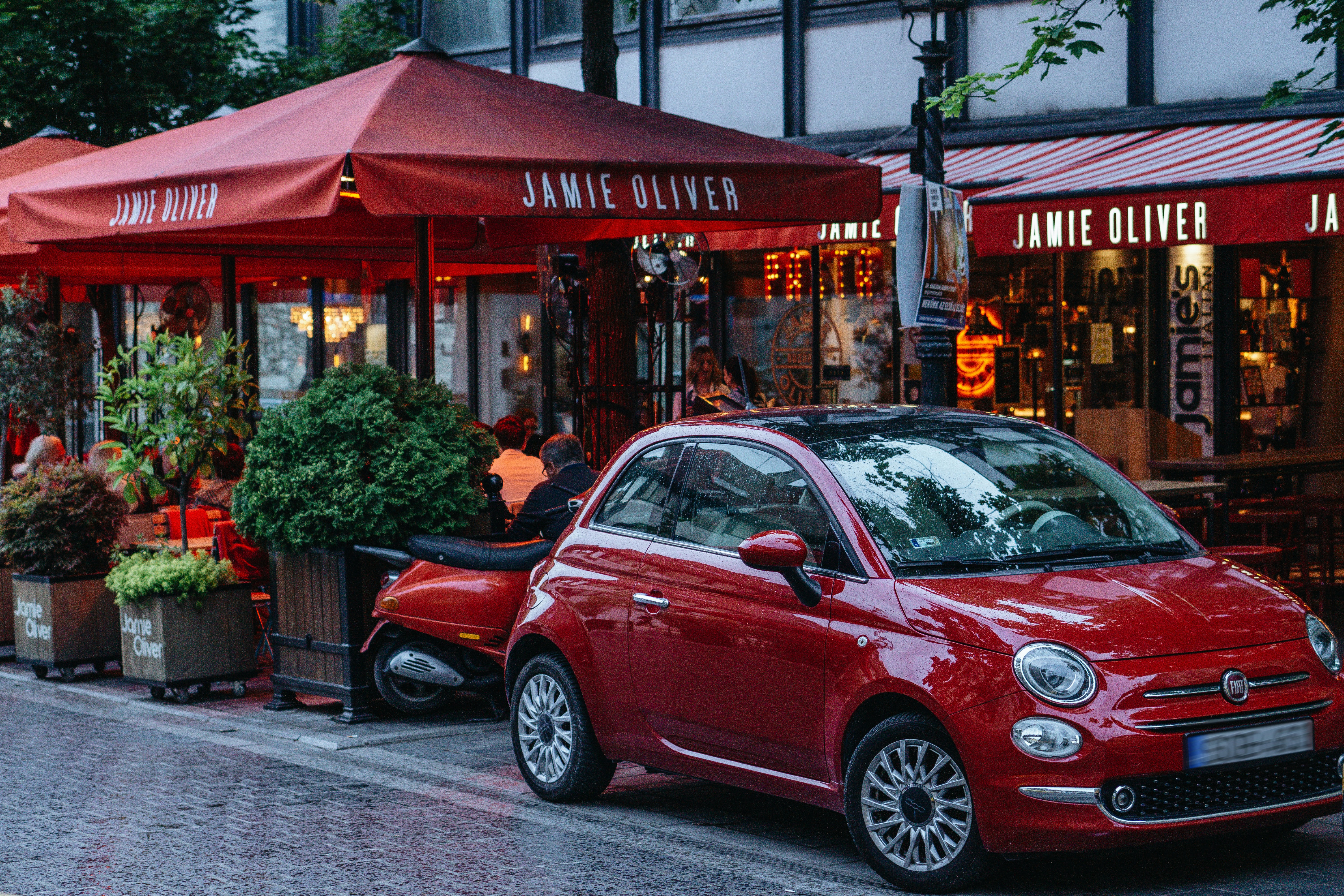 Scarlet Fiat Pausing at the Cobblestone Café Under Jamie Oliver Awnings