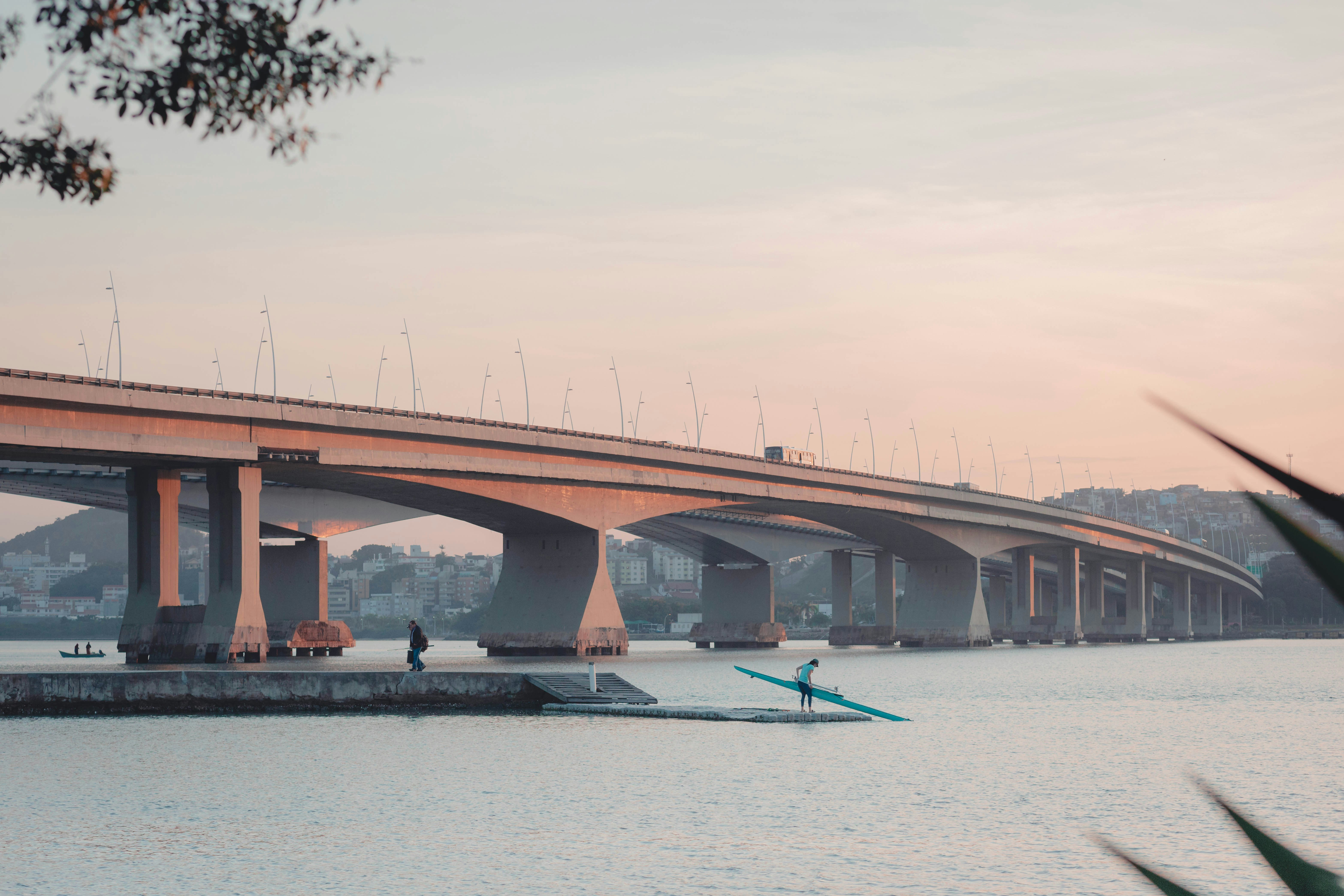 Pastel Dusk Under the Bridge: Paddleboarder on Quiet Currents