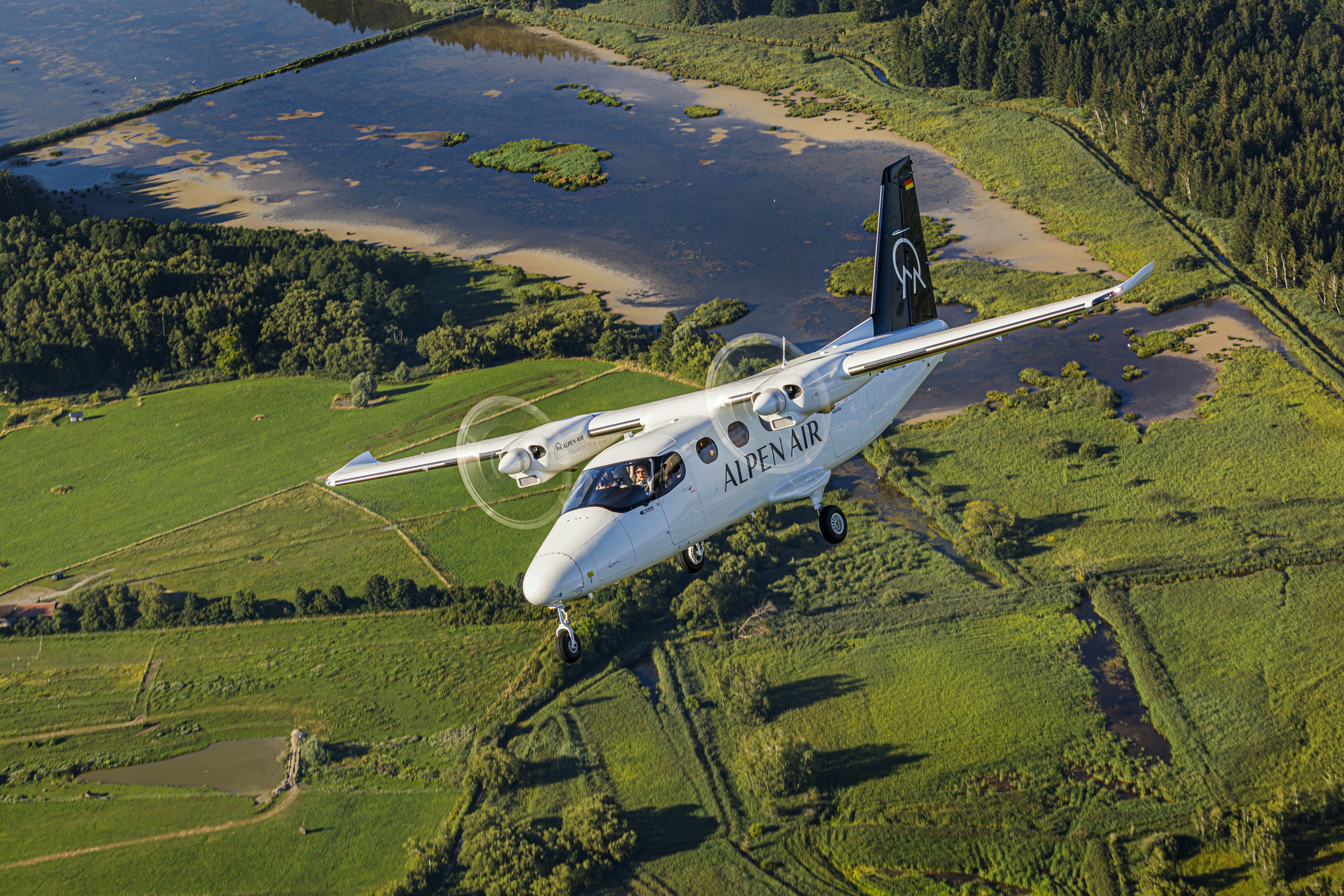 A small plane flying over a lush green field photo – Free Forest Image ...