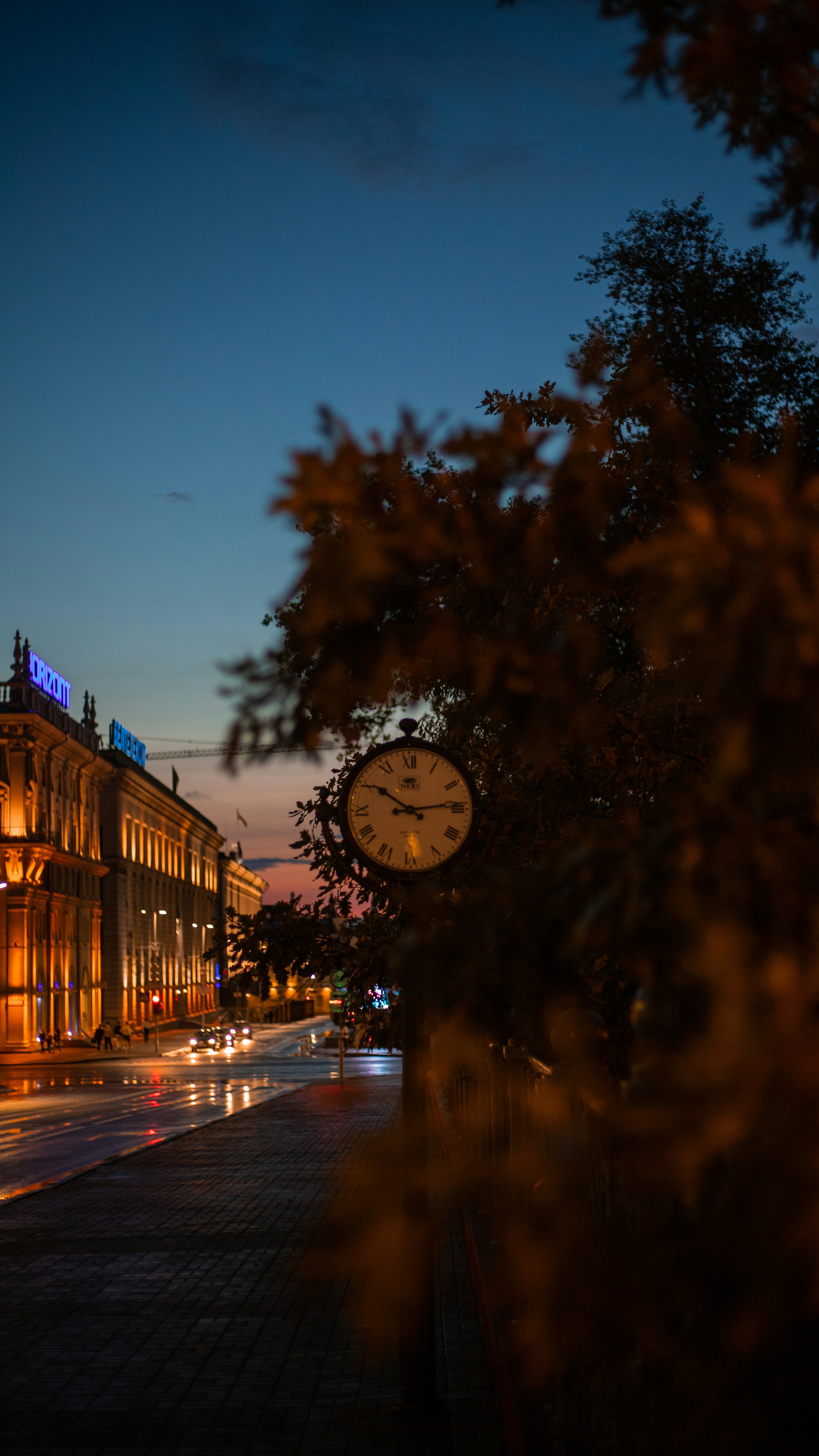 Blue Hour Clock Anchors a Rain-Wet City Street