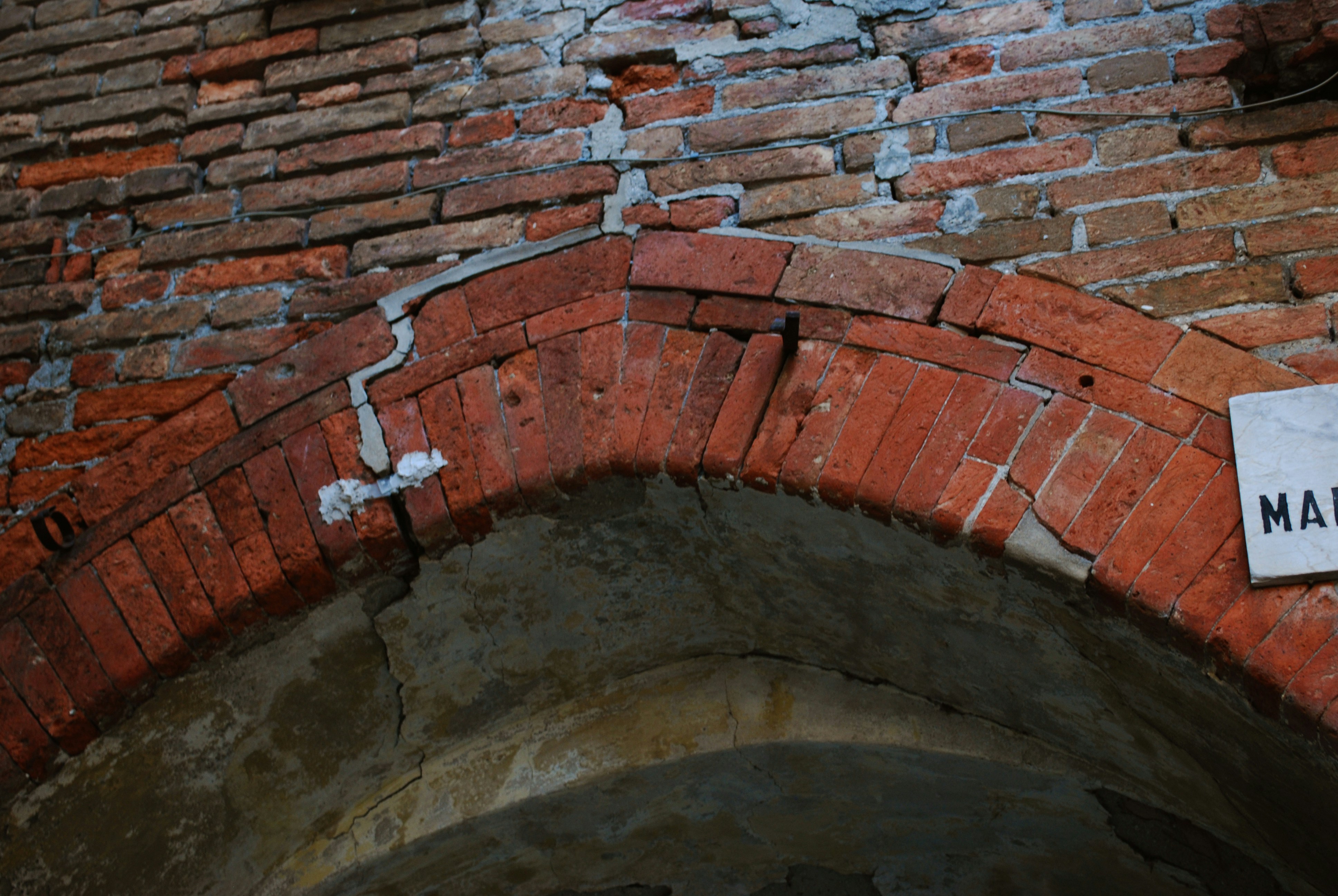 Archway of Time: Weathered Brickwork Framed by a Corner Sign