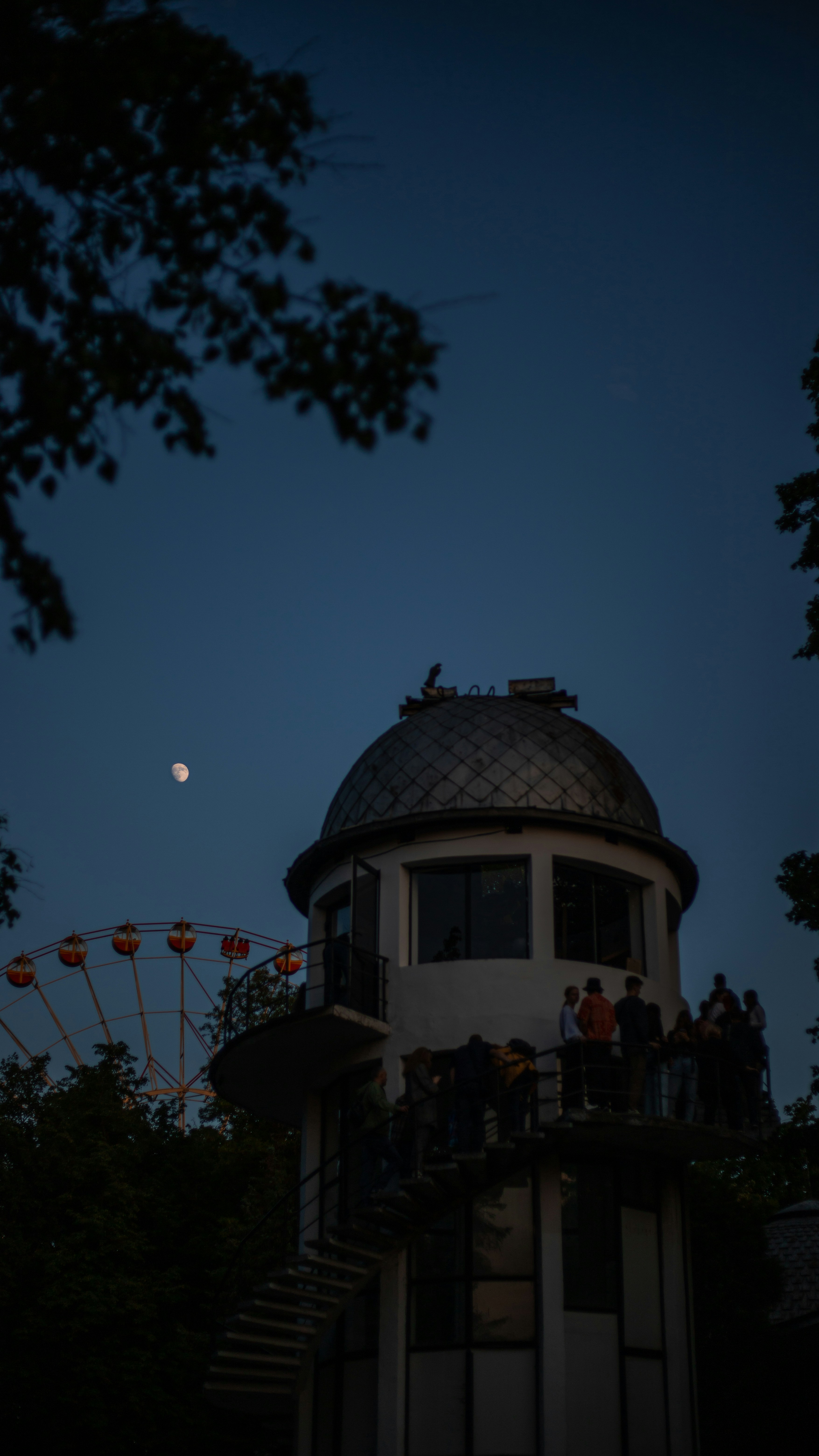 Dome at Dusk: Crowded Balcony Beneath a Moonlit Sky