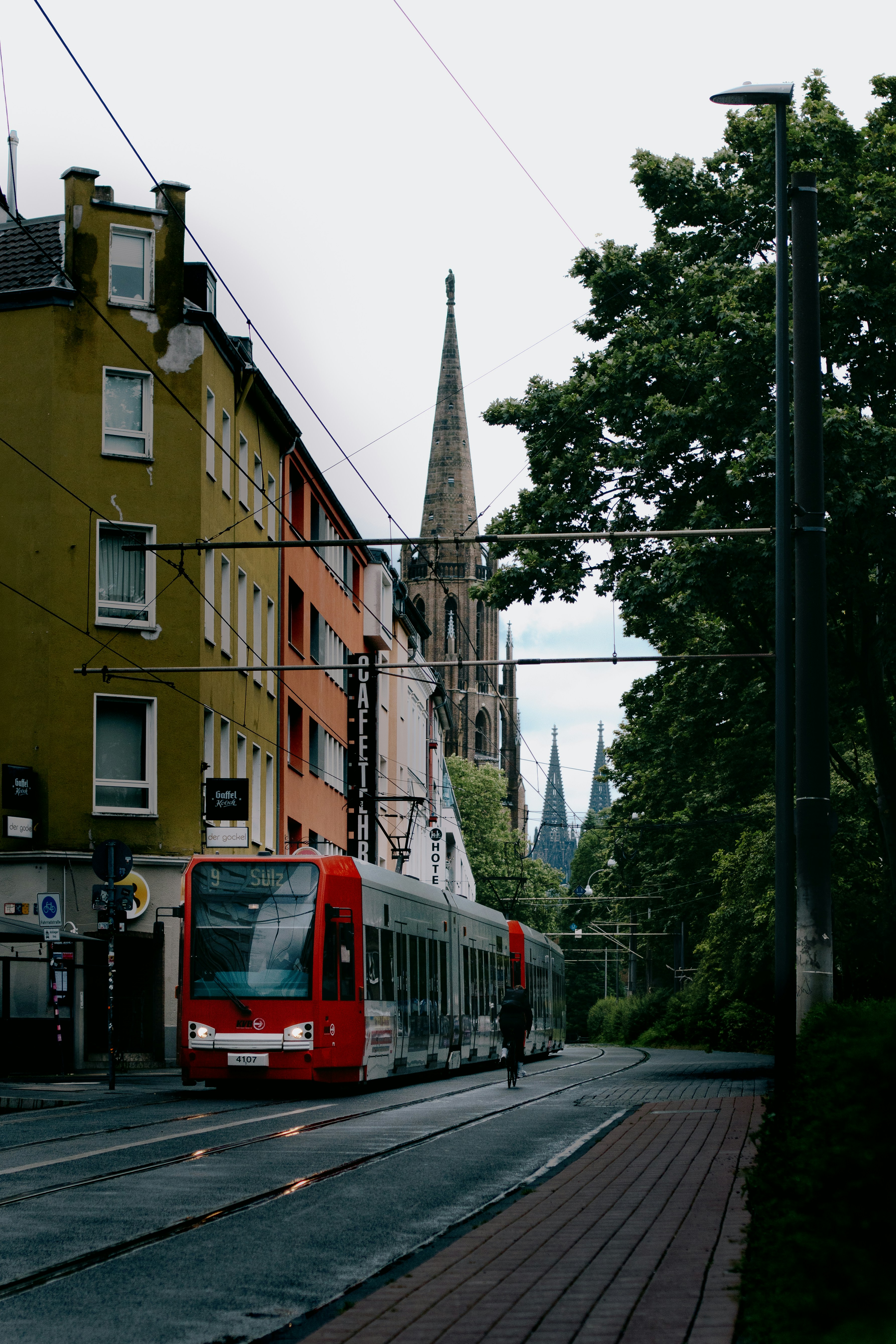 Red Tram threading a narrow European street toward Gothic spires