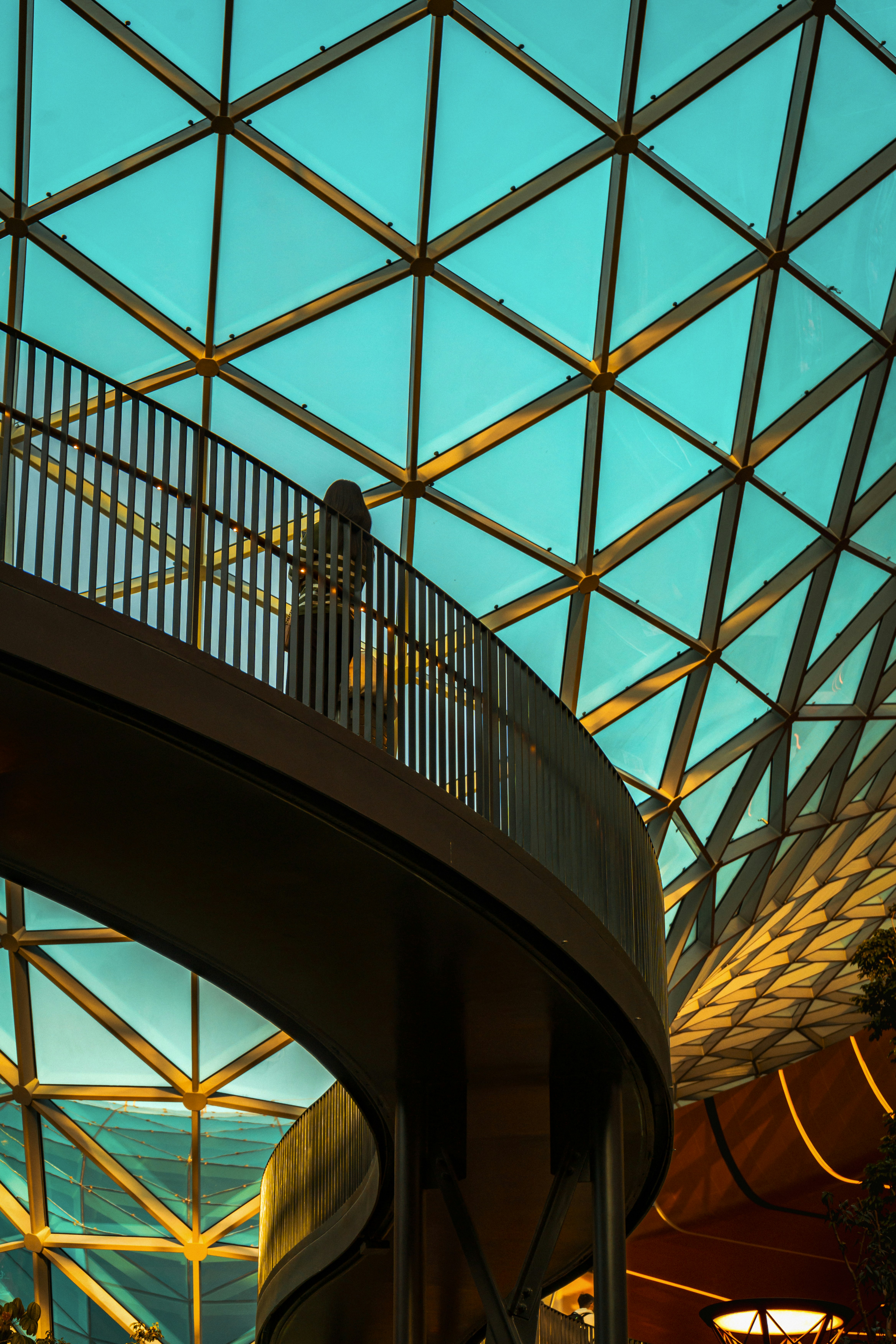 Teal Lattice Overlook: Silhouette on a Curved Balcony Beneath a Glass Grid