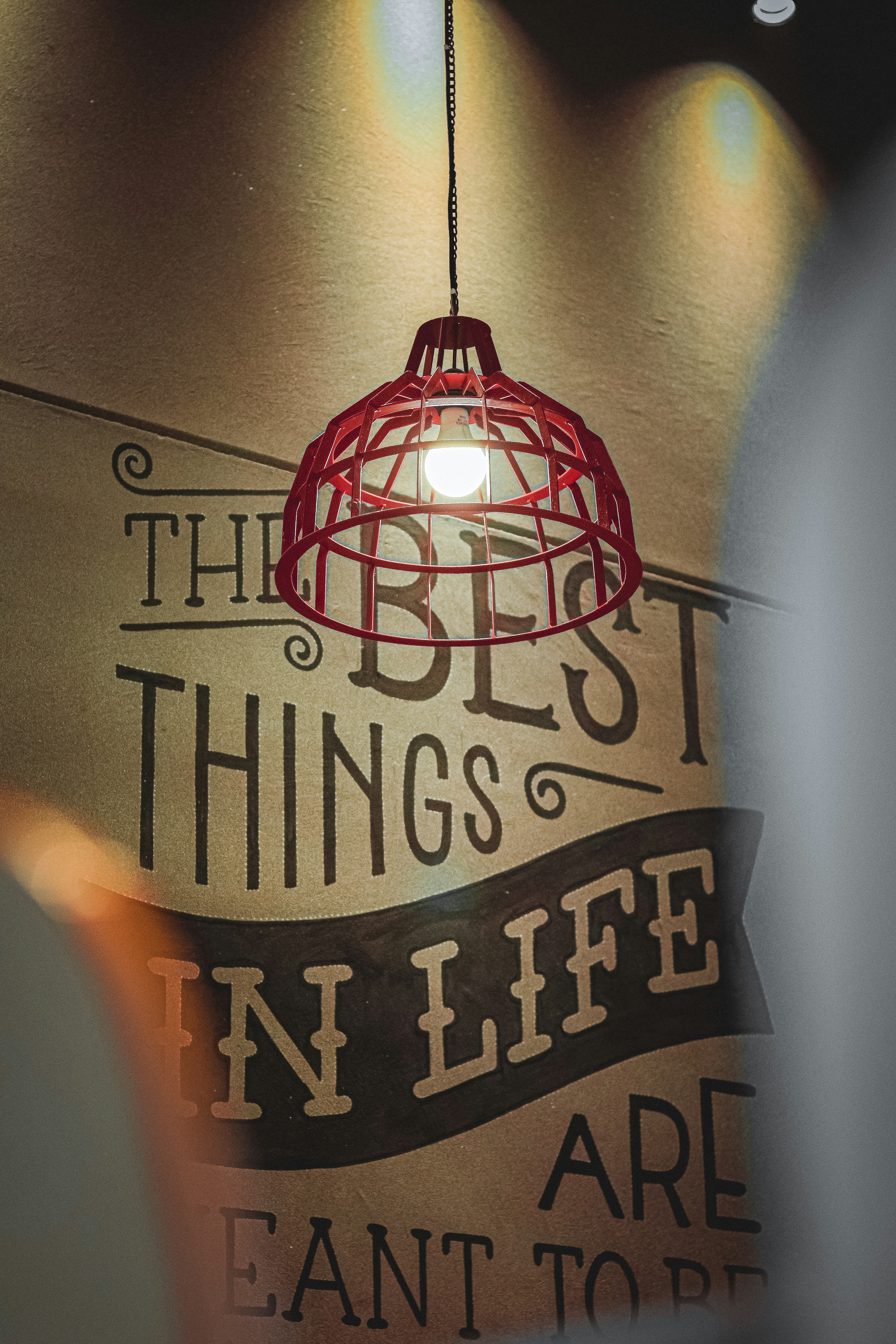 Hanging red lamp casting warm light over a motivational wall quote.