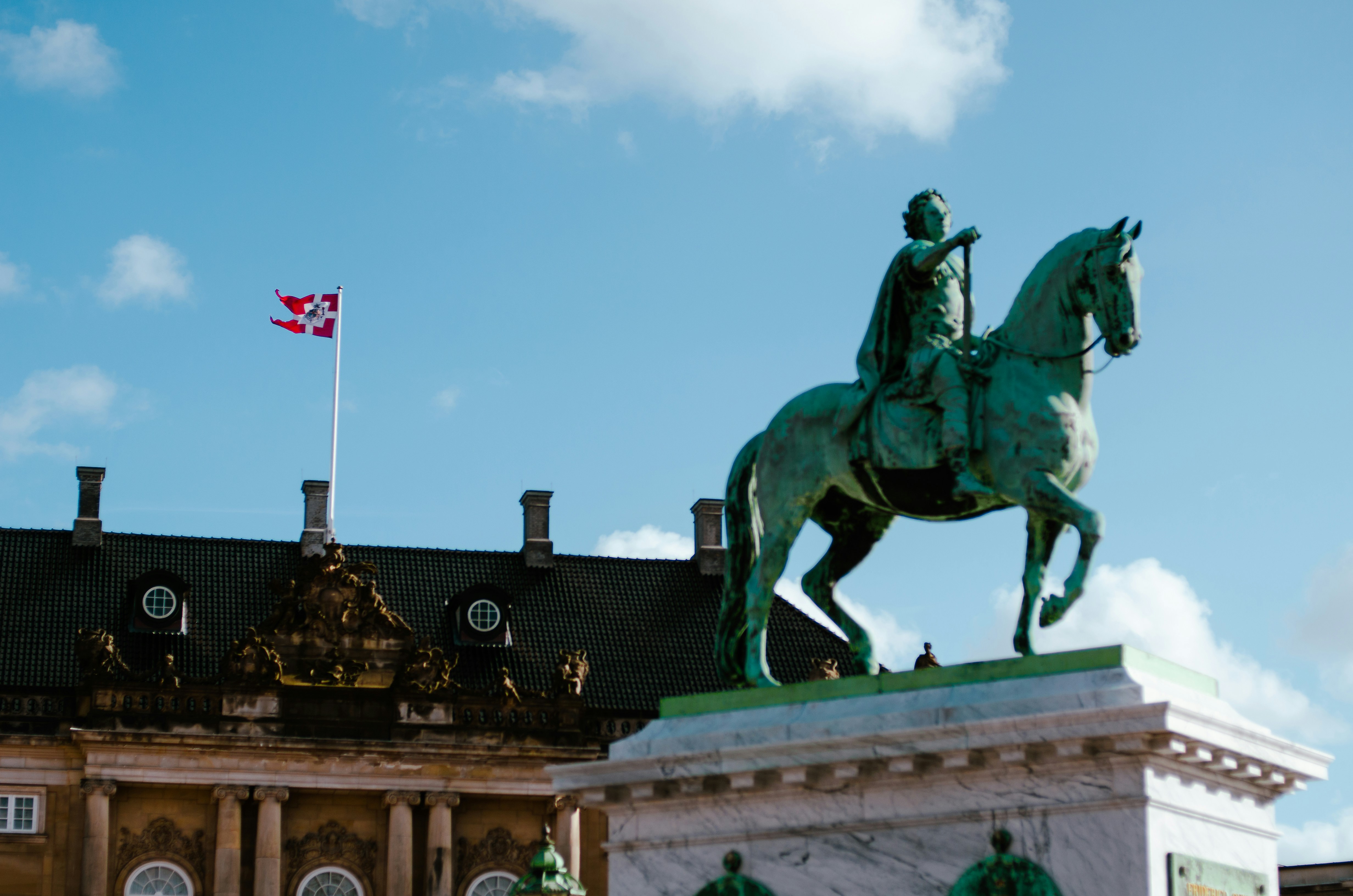 Verdigris Sentinel: Equine Monument Before a Flag-Flanked Facade
