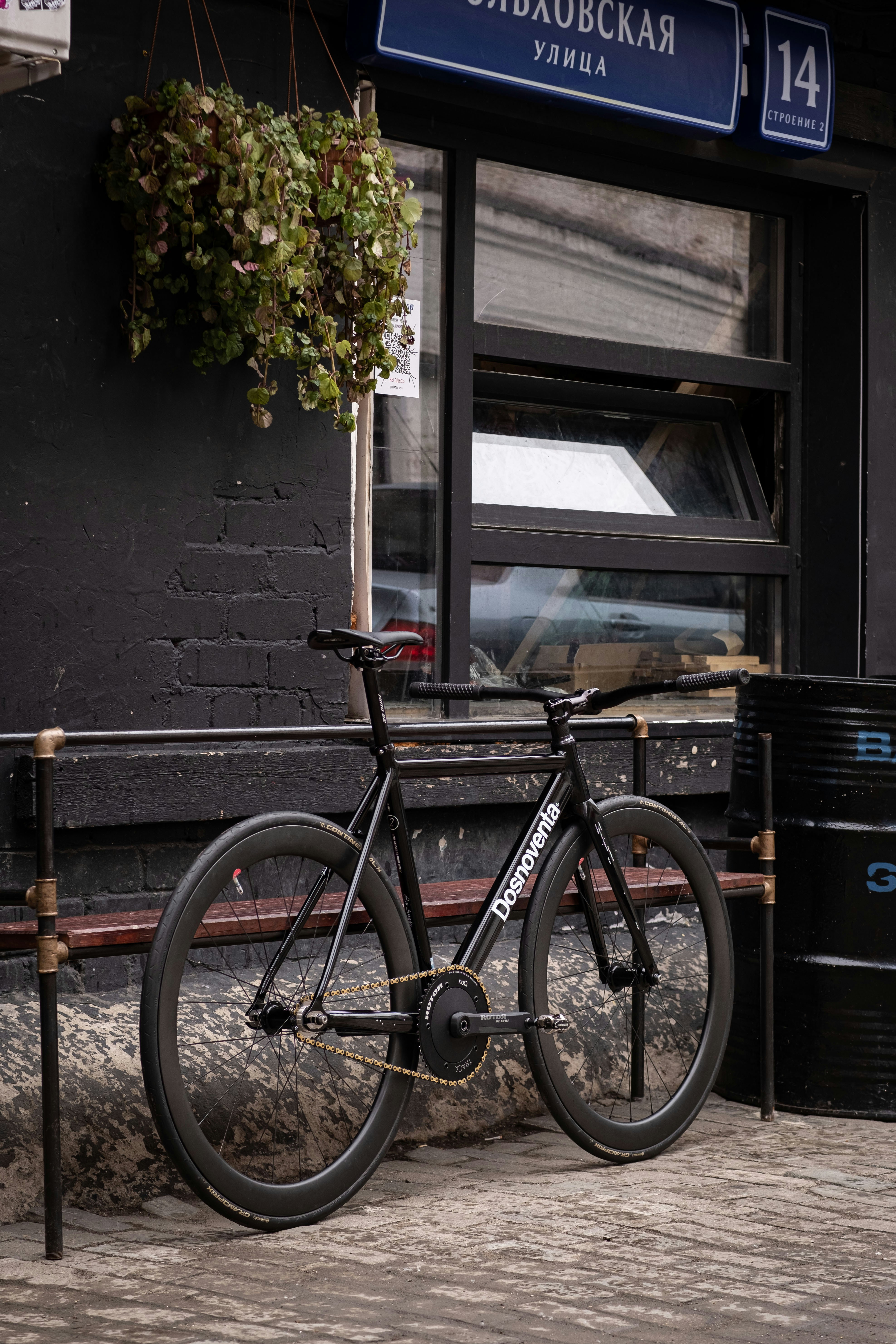Pinarello Resting Against an Urban Brick Wall Under a Blue Street Sign