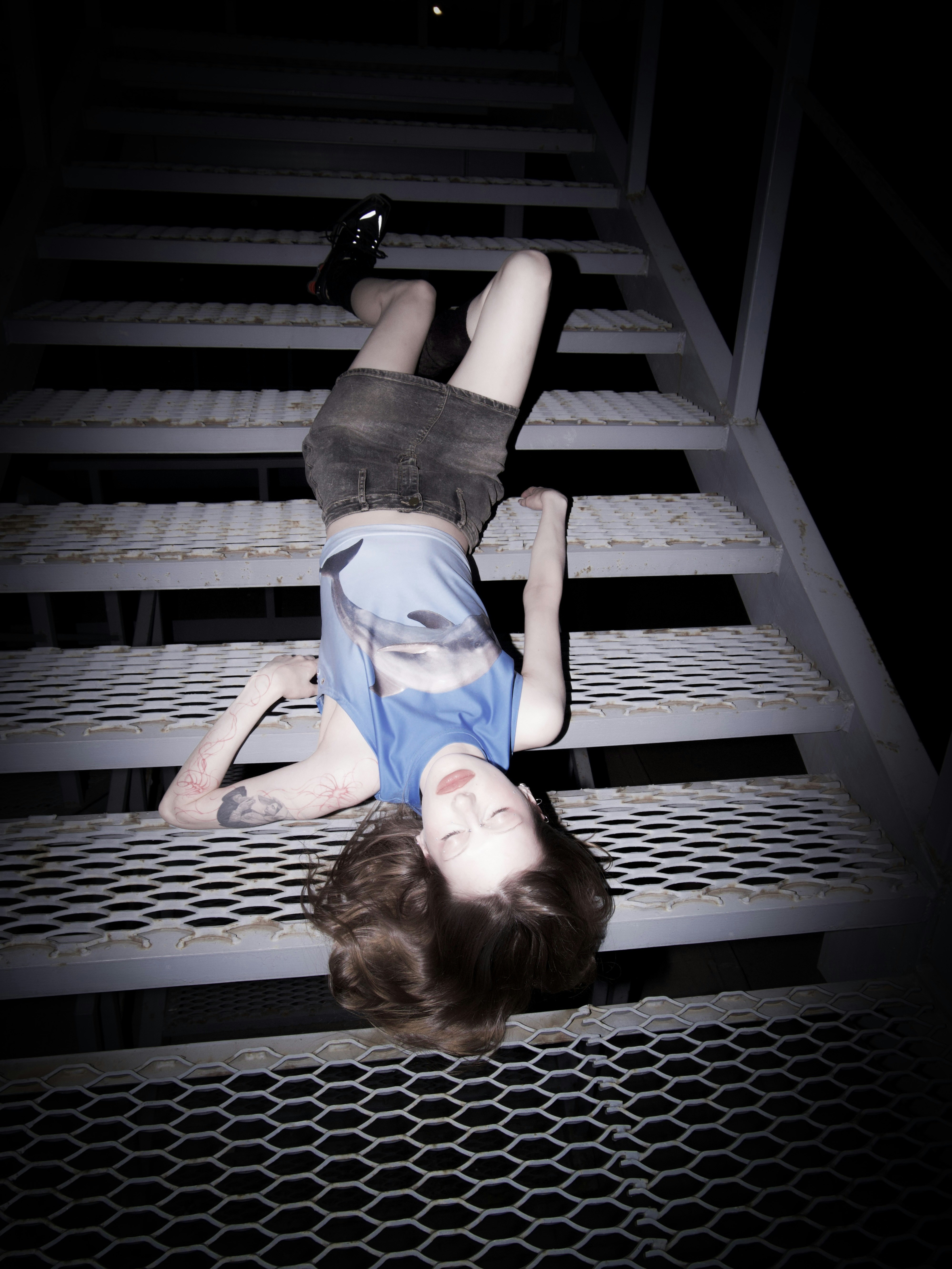Upside-Down on Steel Steps: A Night Portrait Amid Industrial Gratings