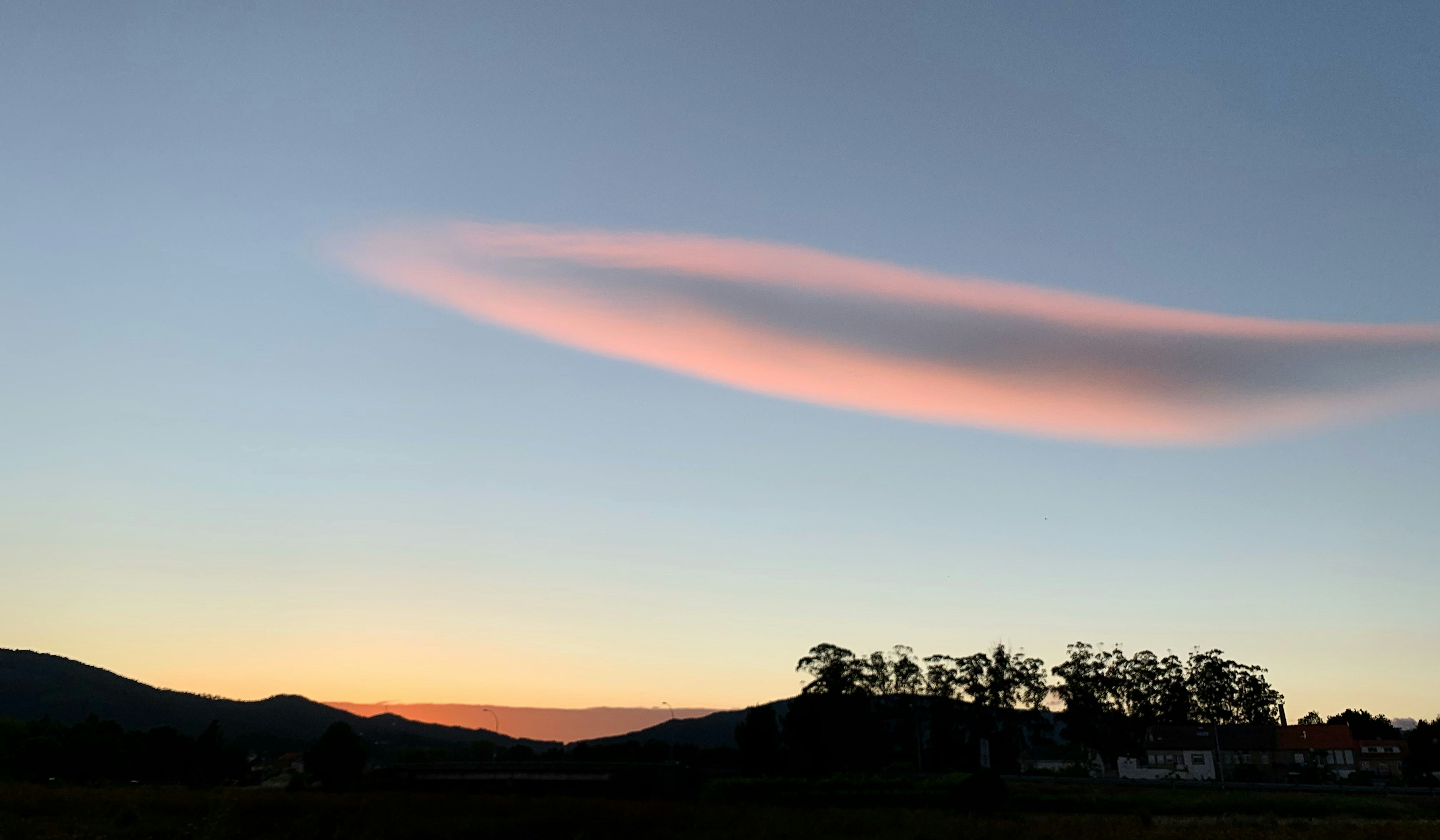 A long cloud is in the sky over a field photo – Free Dark Image on Unsplash
