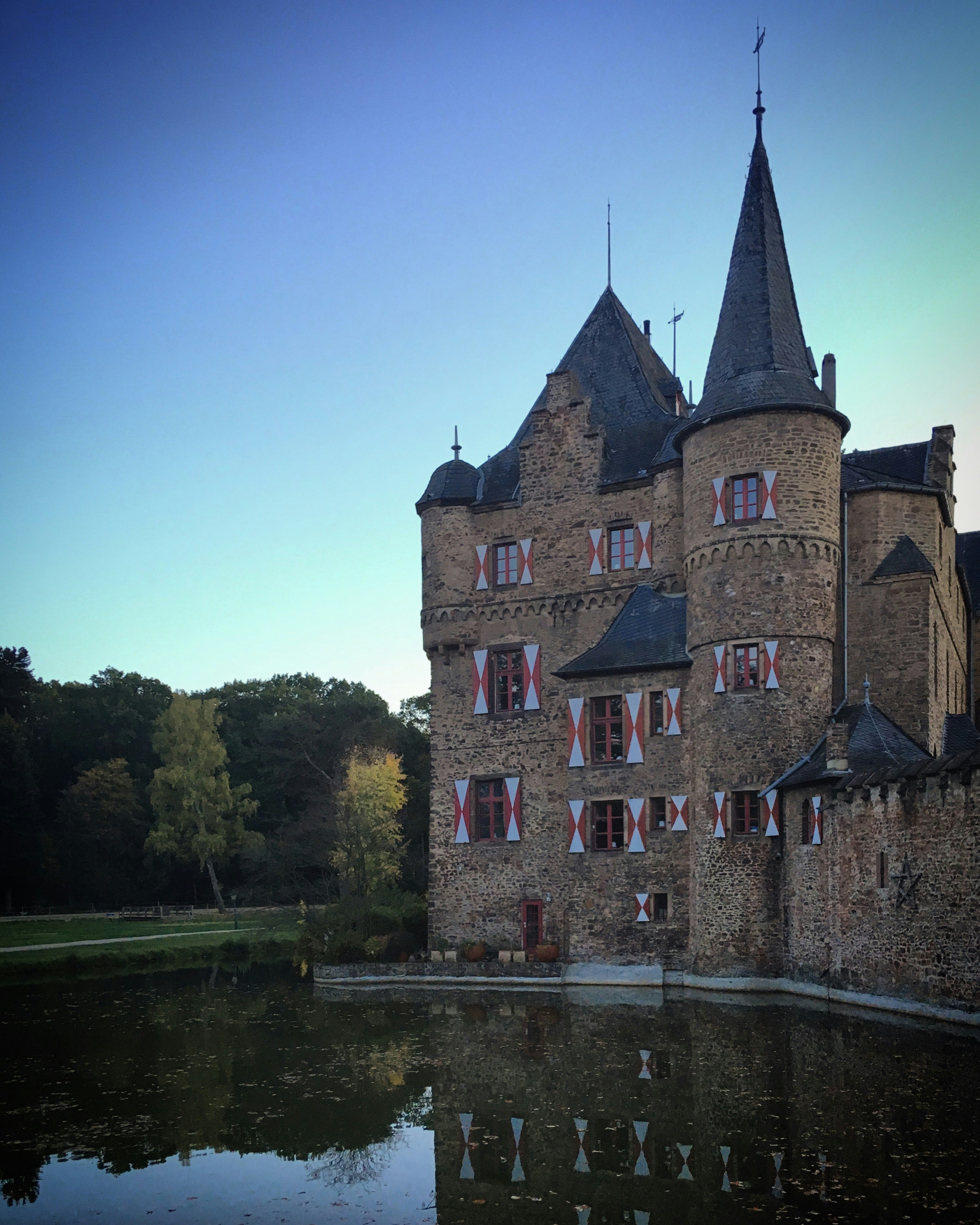 Burg Satzvey castle reflected in the water of the pond, Satzvey, North Rhine-Westphalia, Germany, October 2018