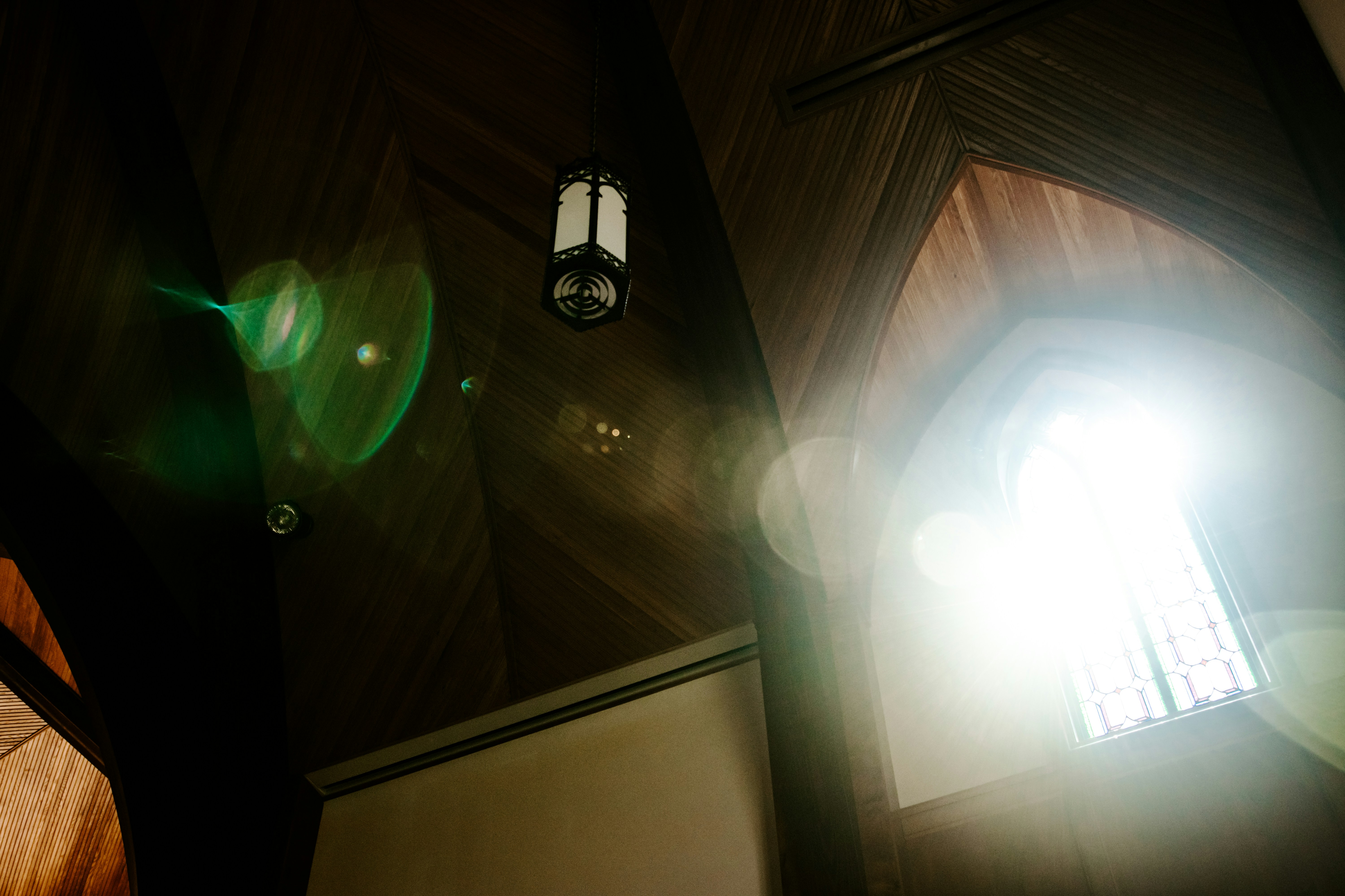 Sunlit Timber Vaults: Lantern and Lens Flare in a Quiet Chapel